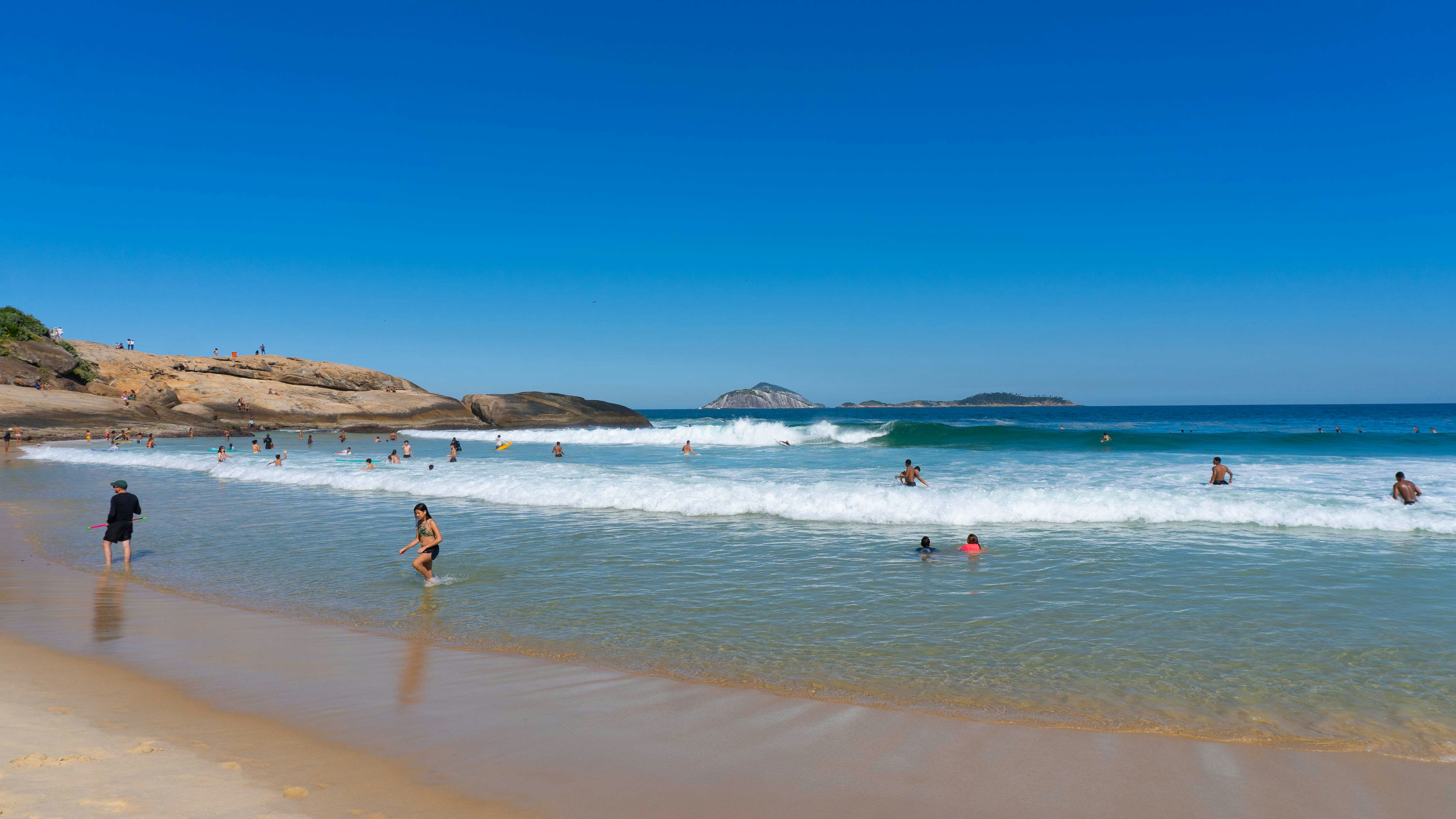 Blue Horizon at Mid-Beach: A Quiet Tide Amid Surfing Silhouettes