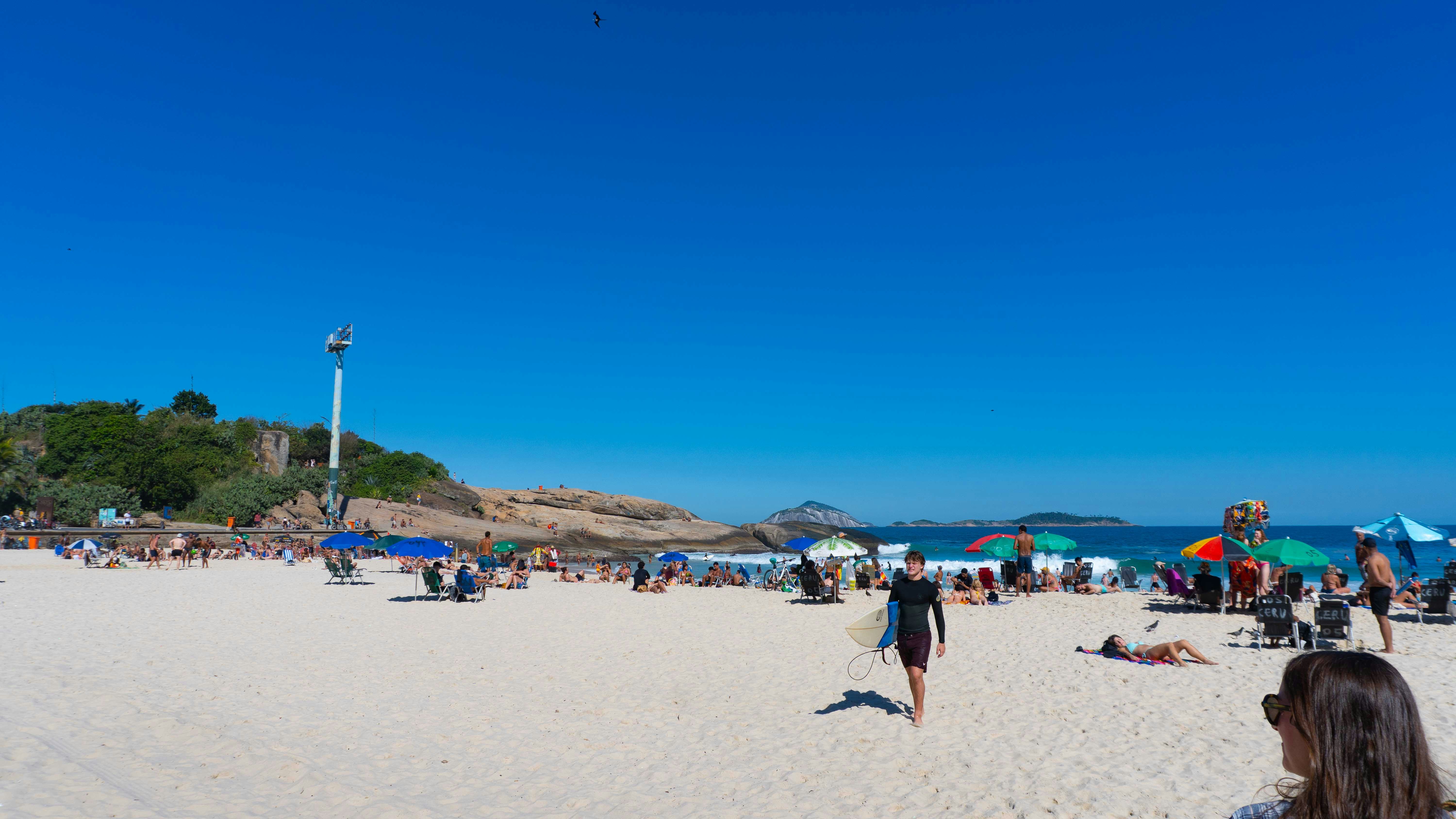 Sunlit Cove: Beachgoers Scatter Across Fine White Sand Beneath a Pristine Blue Sky