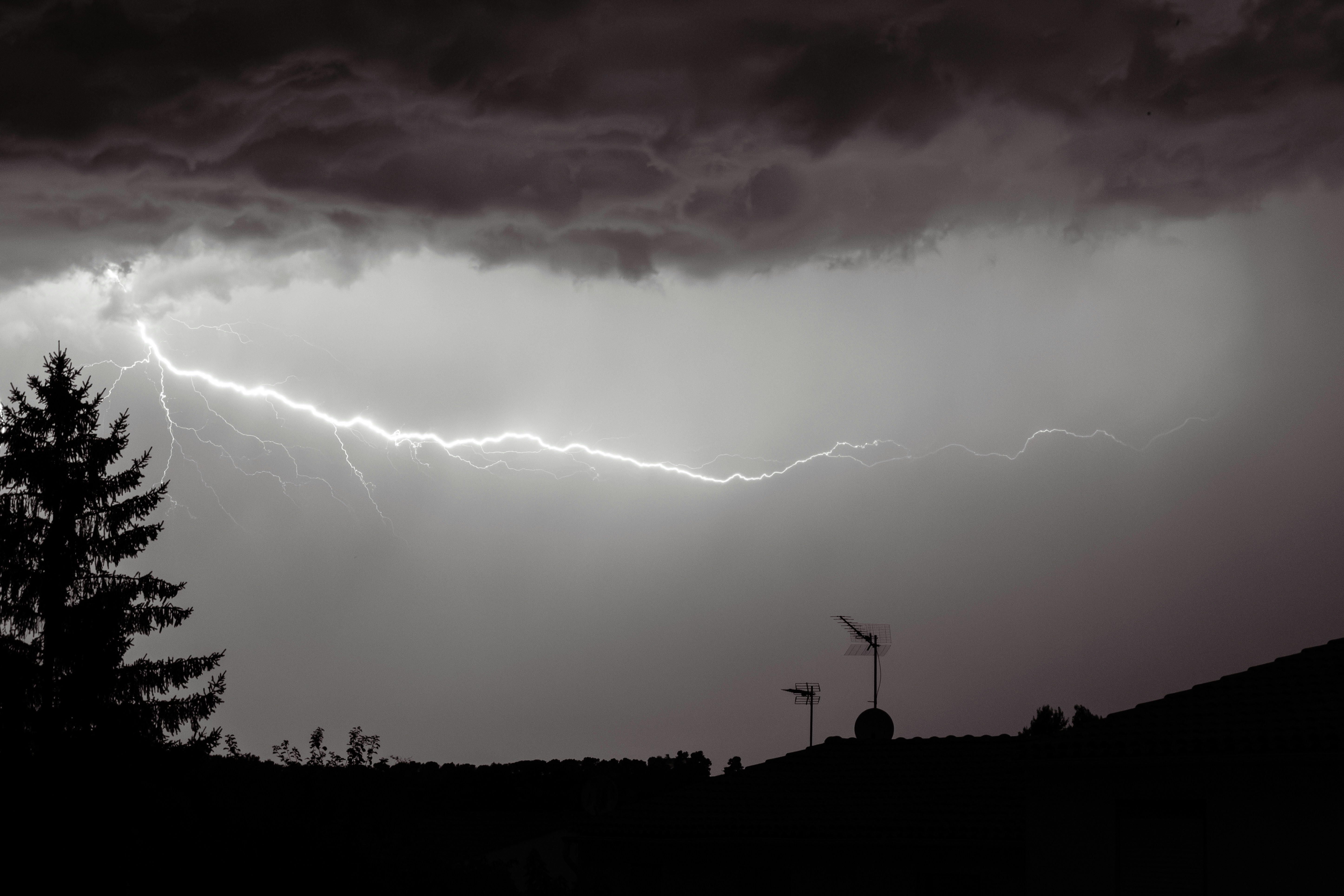Forked twilight: jagged lightning over a quiet rooftop horizon