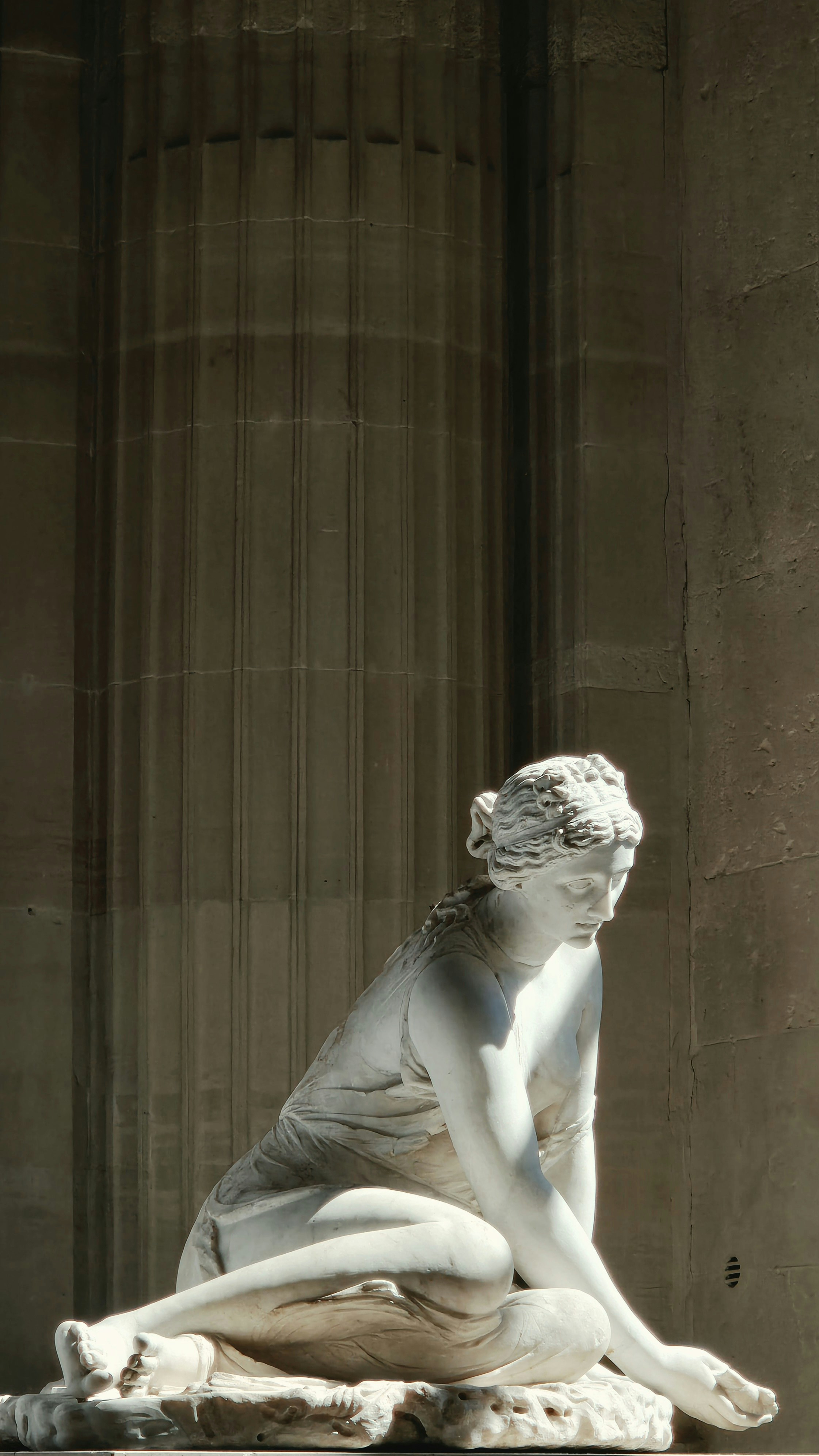 Sculpted Solitude: A Marble Angel Beside Stone Columns