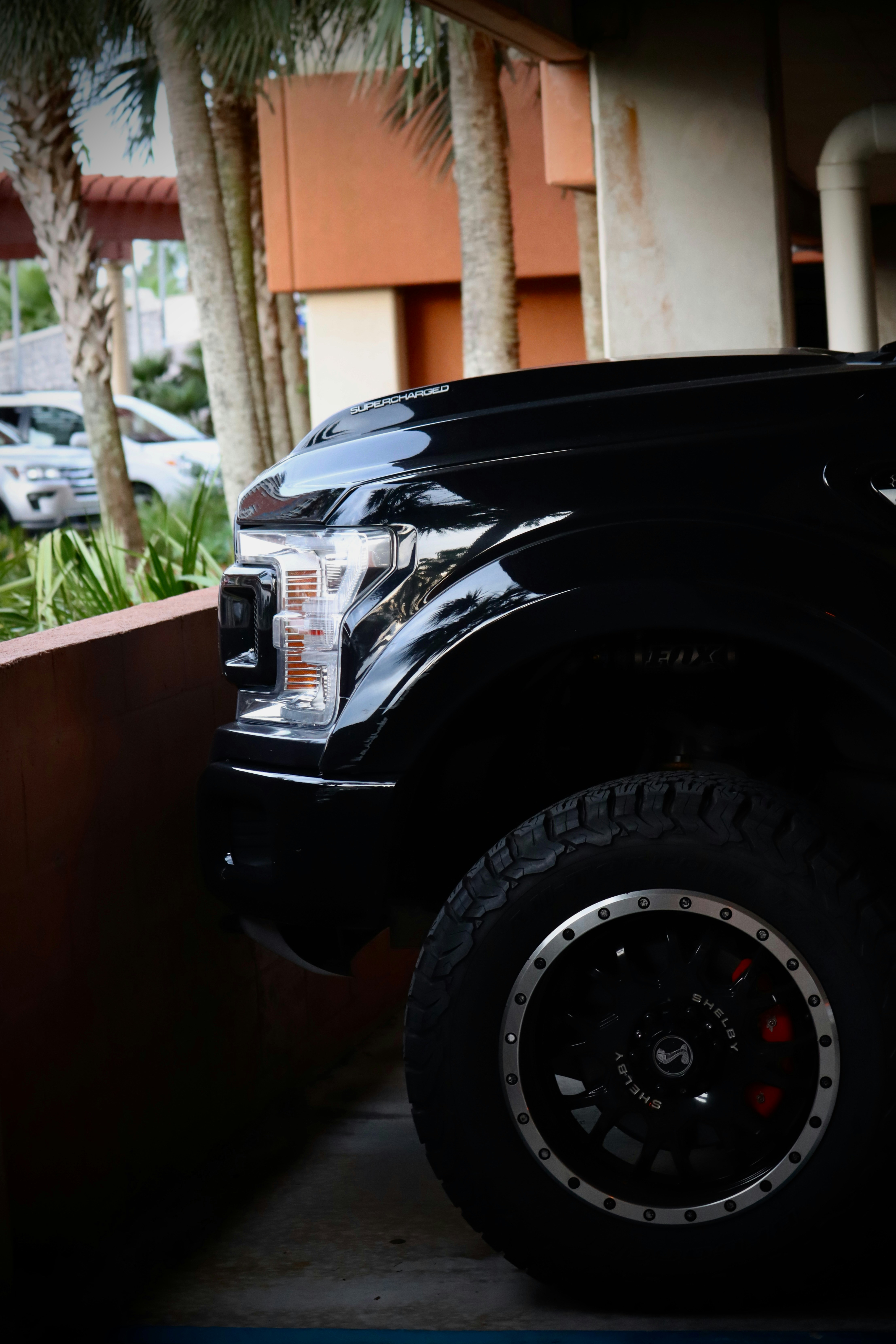 Black pickup with bold wheel and glossy hood under a canopy