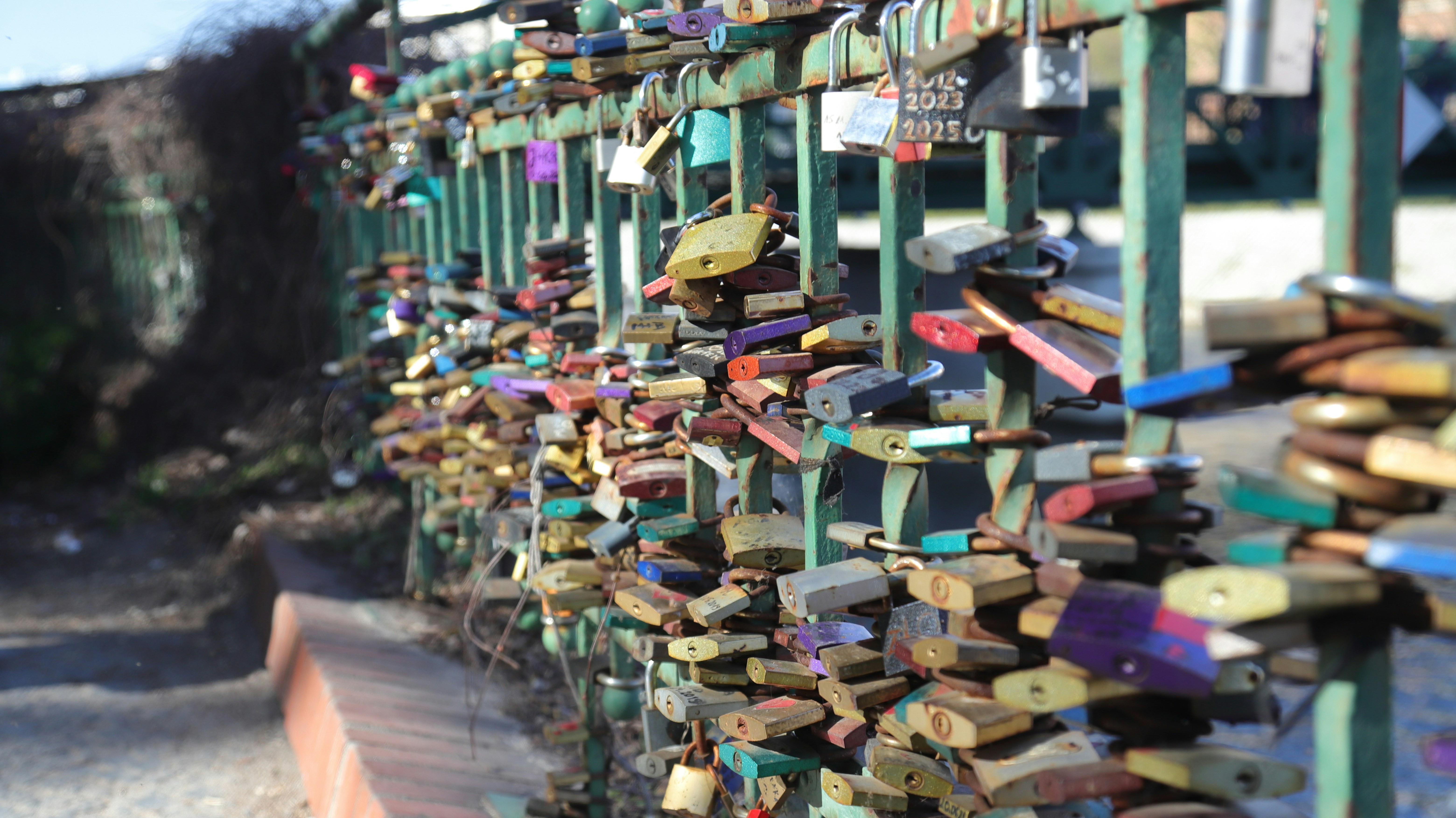 Locked Wishes: a wall of colorful love padlocks by daylight