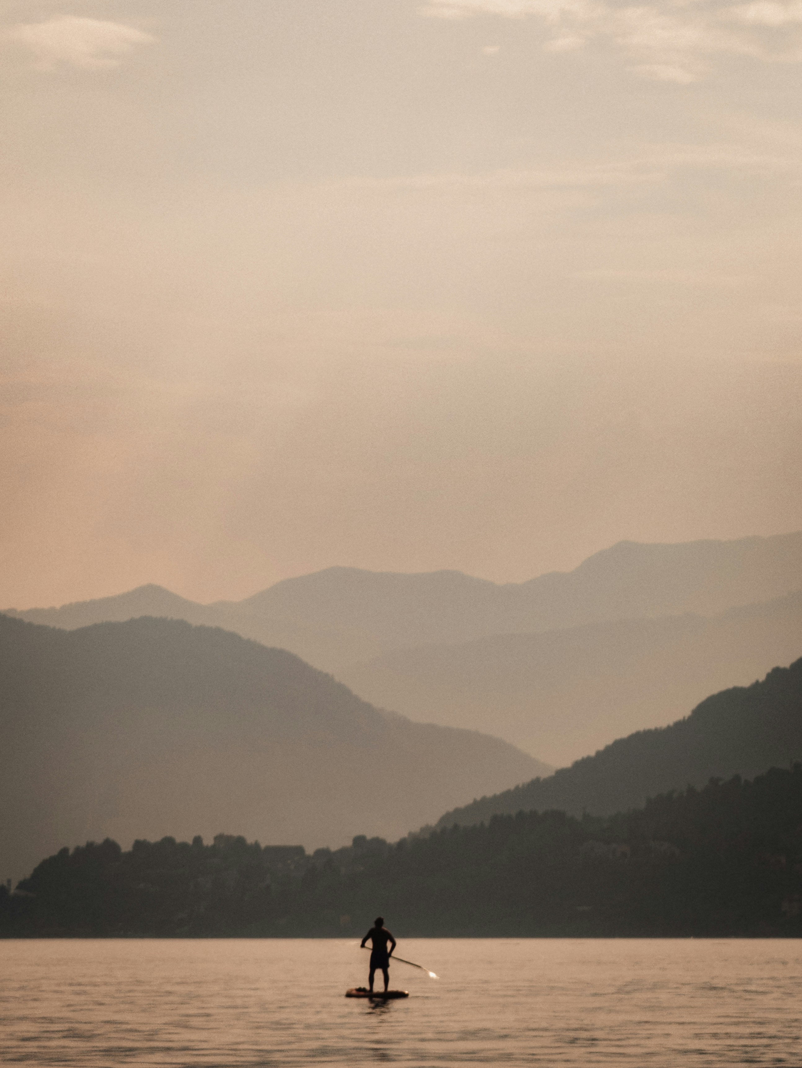 Solitary Strokes: A Surfer's Quiet Ride Across Dusk on Glassy Water