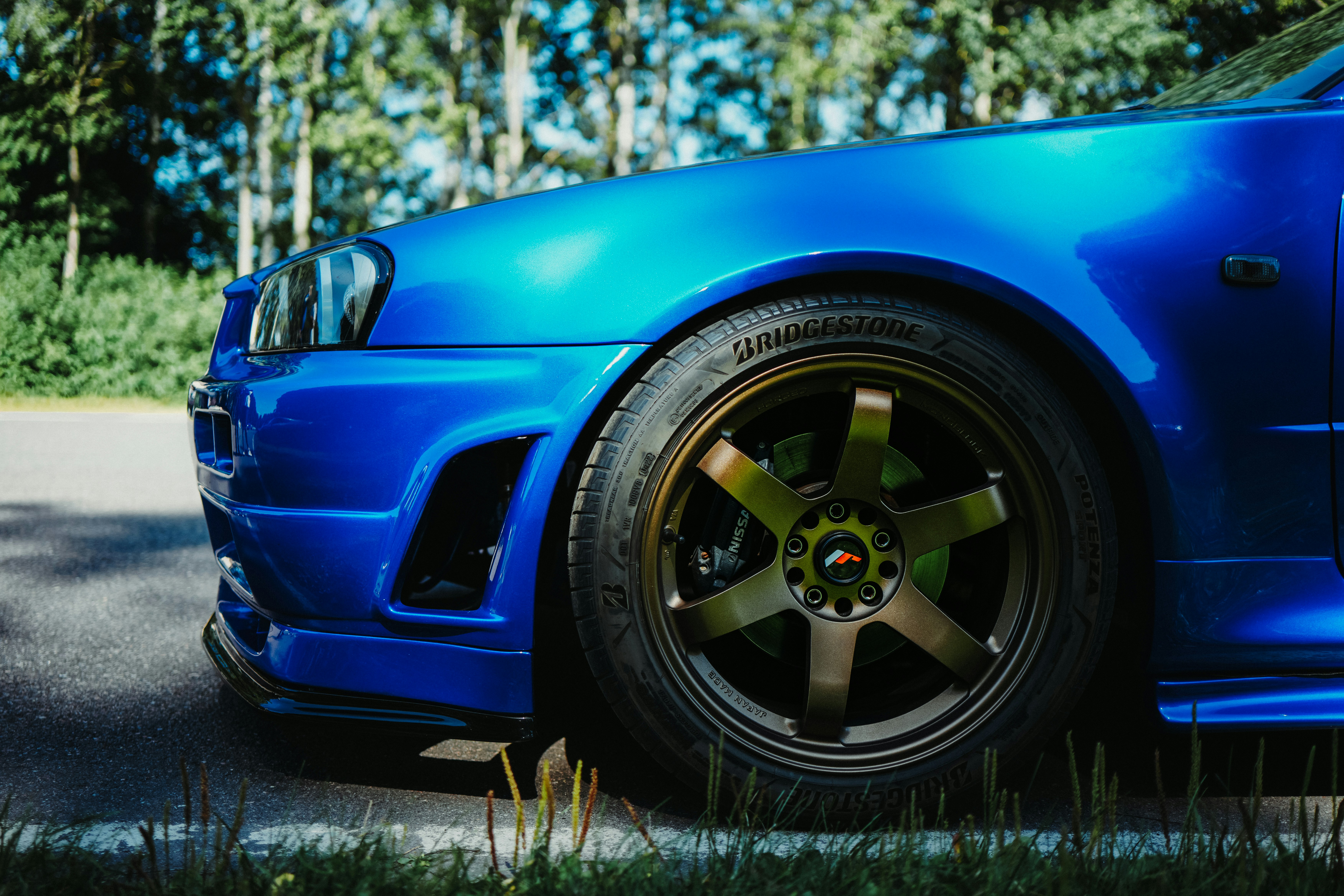 Low-Angle Shot of a Blue Performance Car's Wheel and Front Facade