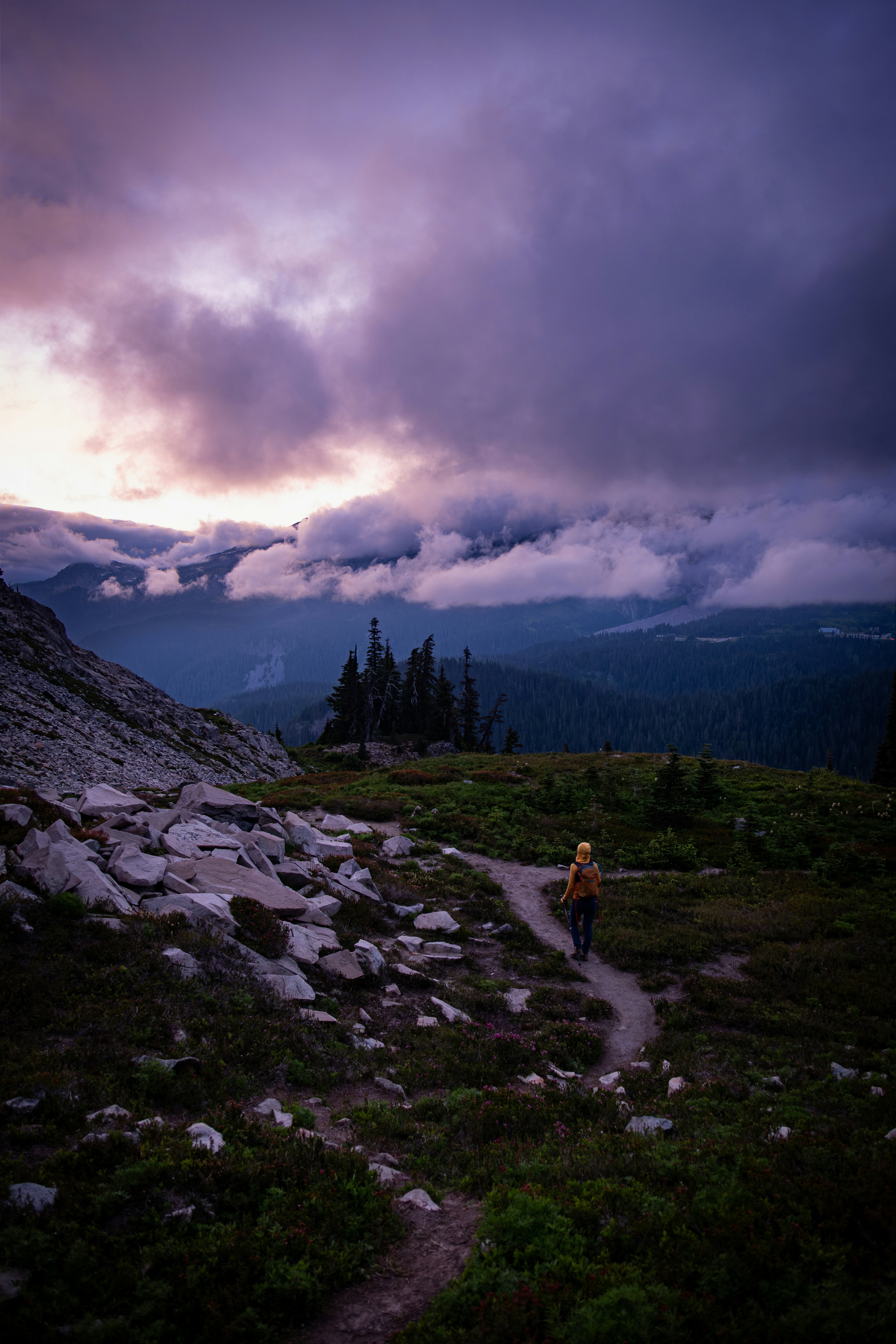 Trail to the Edge: Lone hiker beneath a stormy alpine sky
