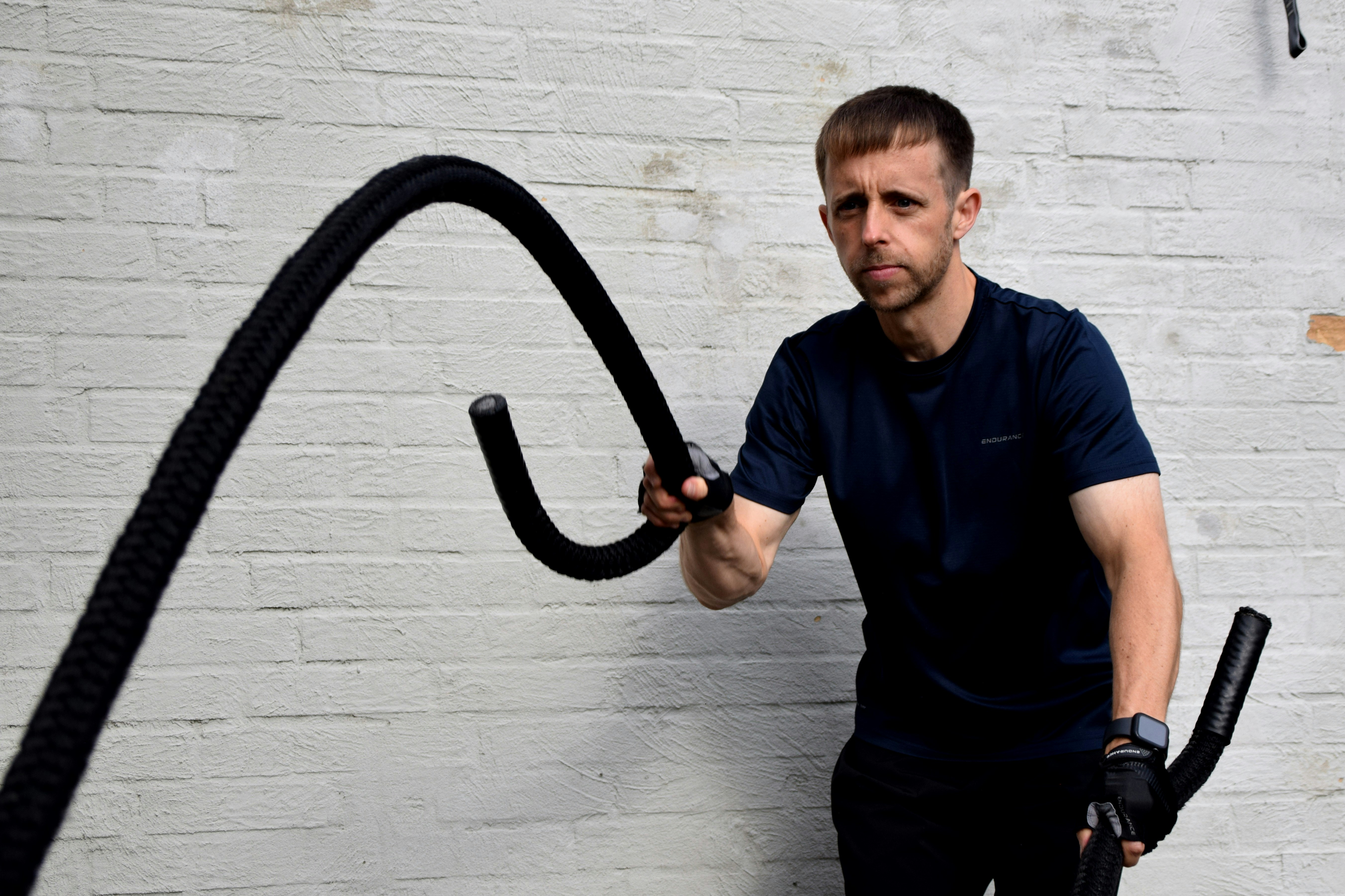 Arms Against the Coil: A Warrior in Dark Tee vs. a Spiraling Hose