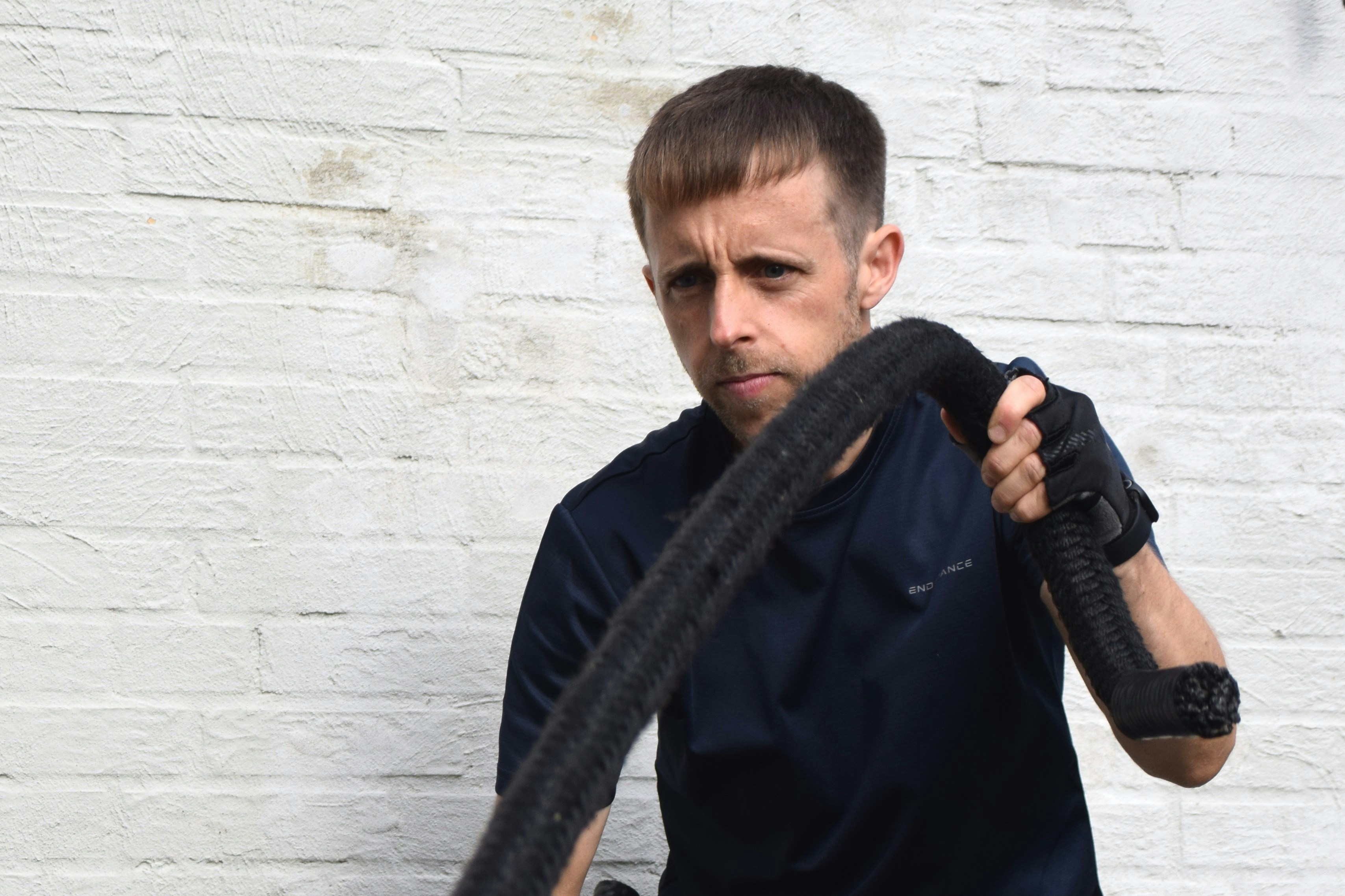 Grip and Focus: A Shot of Determined Strength Against a White Brick Backdrop