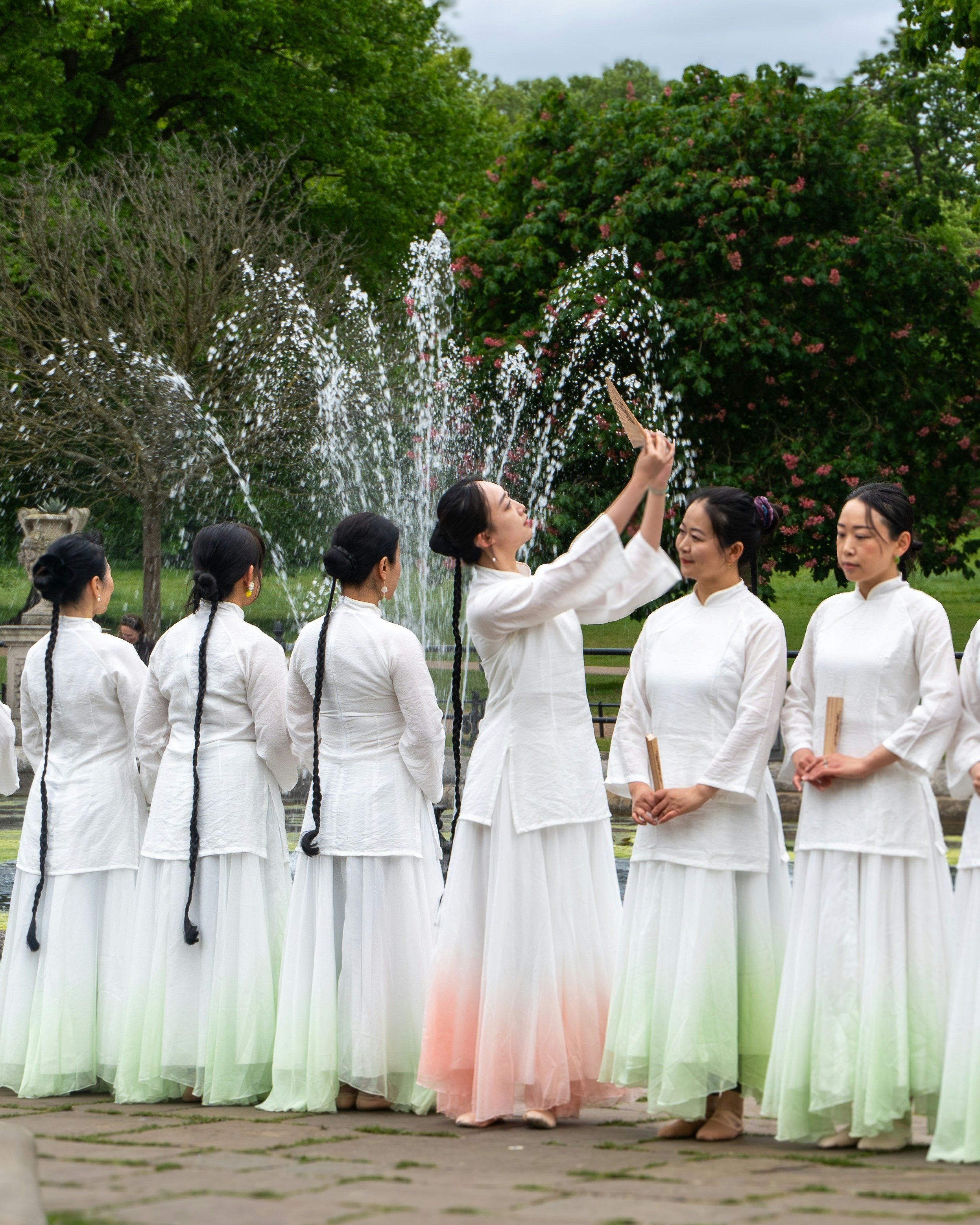 Grace in White: A Collective Moment Under the Garden Fountain