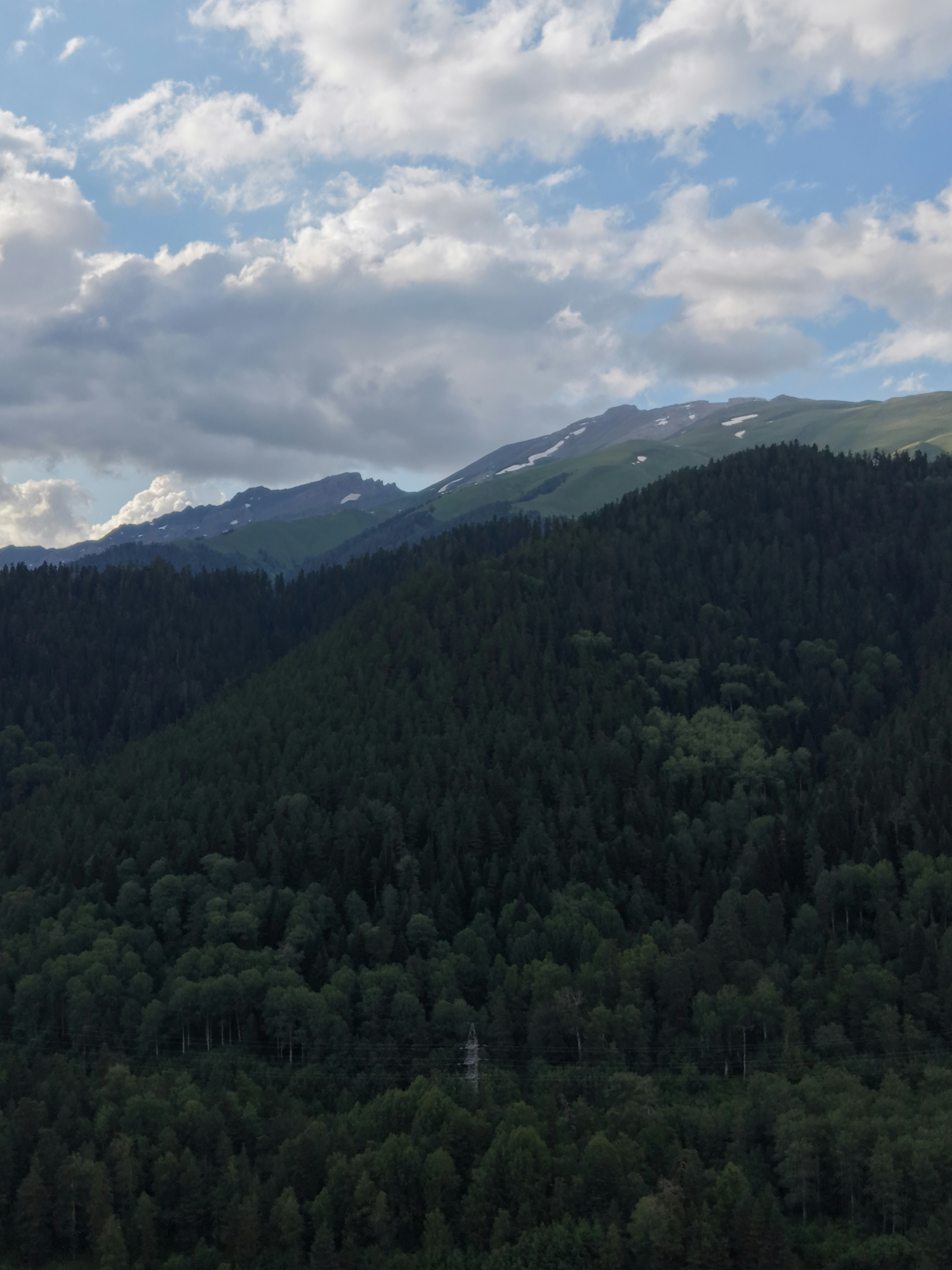 Verdant Peaks under a Sky of Puffs and Light