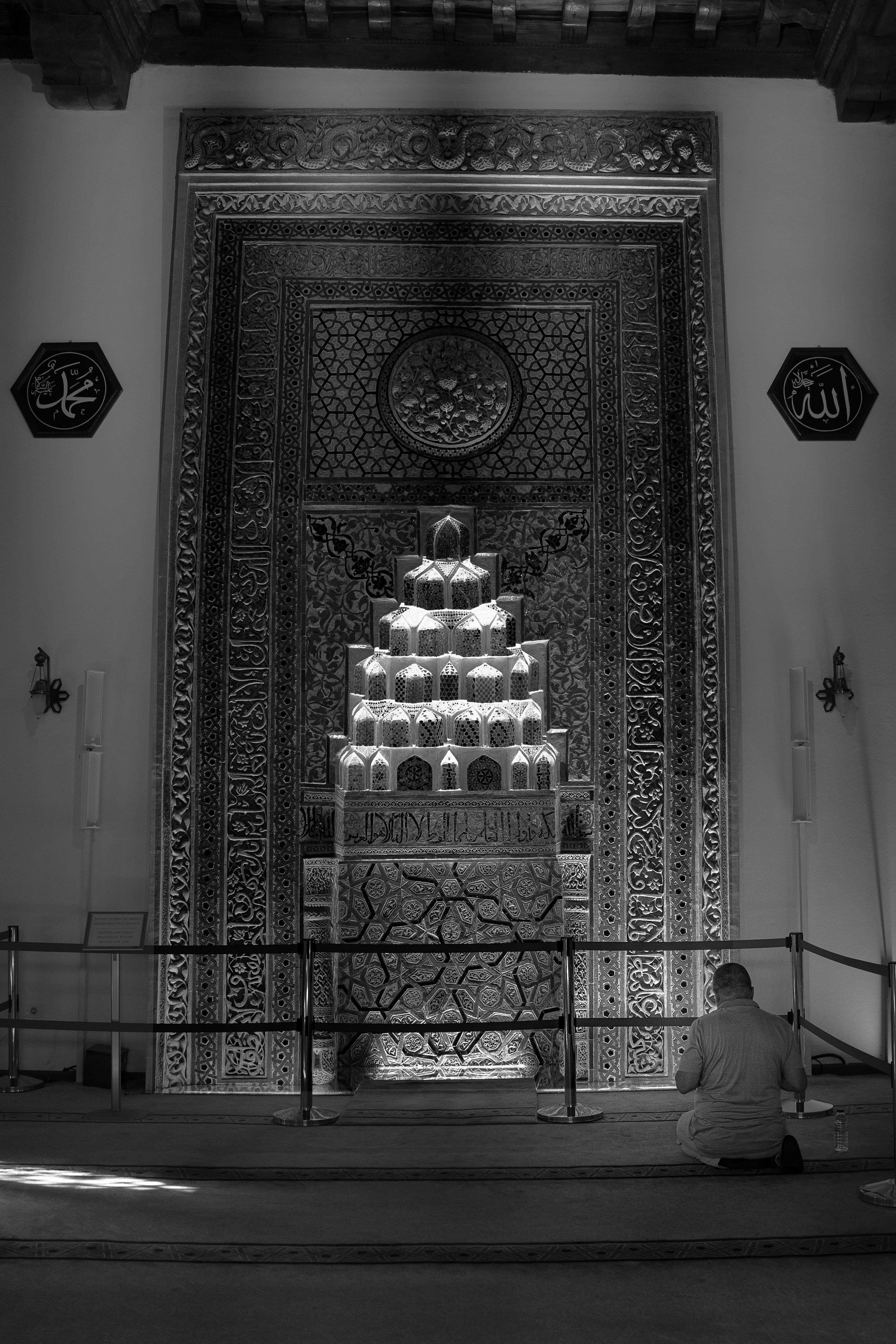 A solitary worshipper and the carved shrine: quiet reverence before a tiered reliquary
