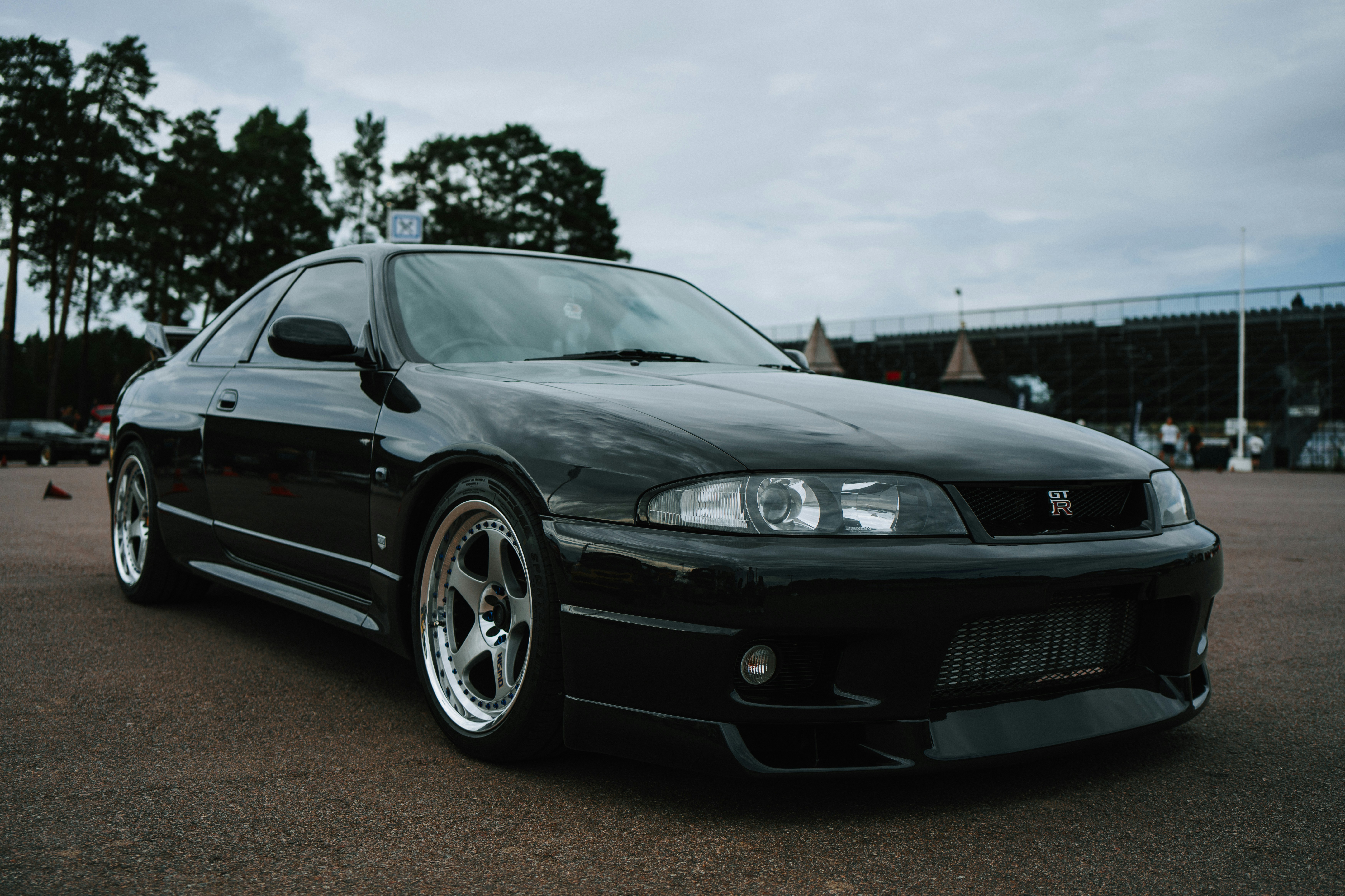 Low-slung black coupe in an empty lot with a modified stance