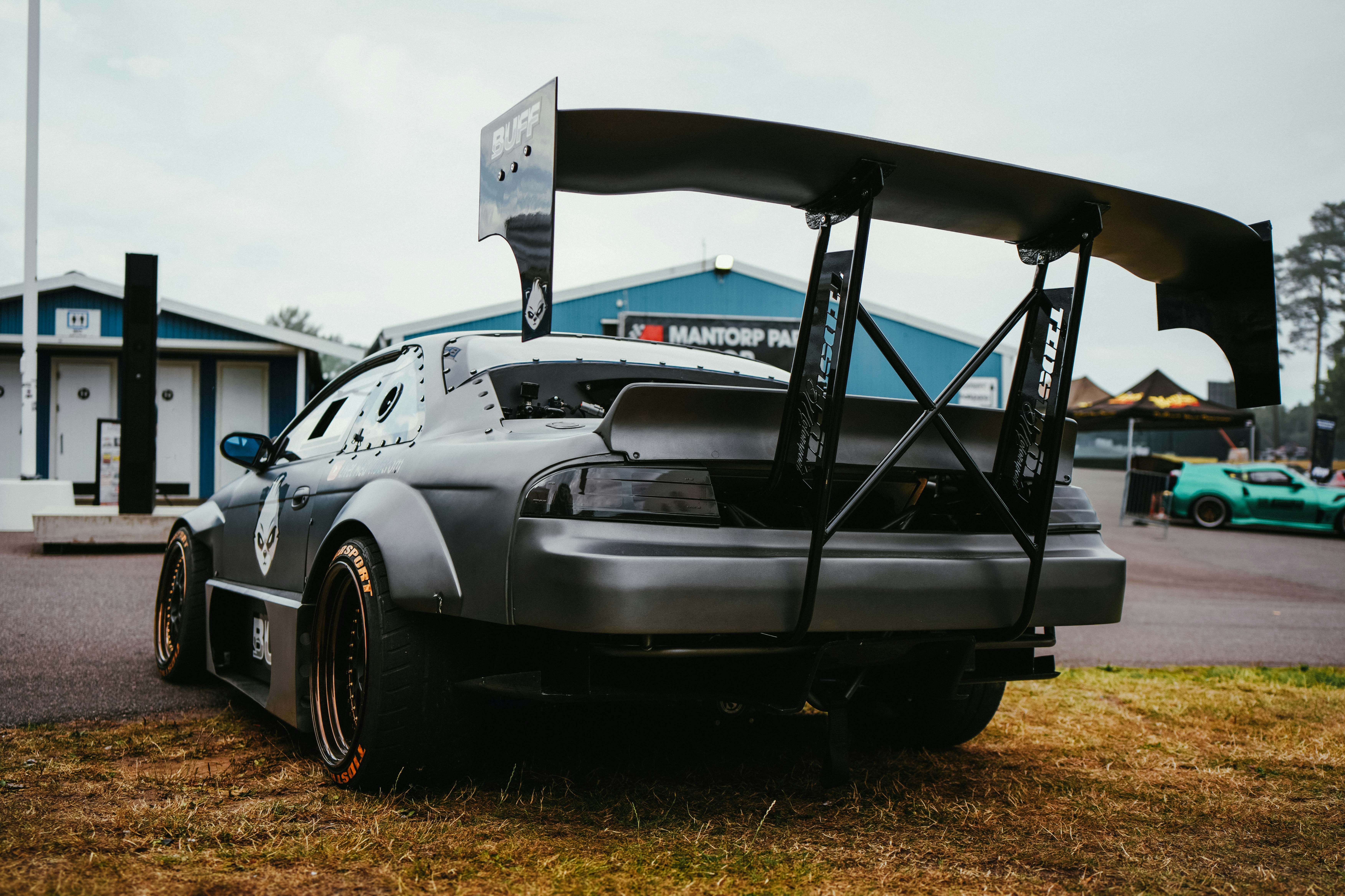 Rear Wing and Wide Stance: A Midnight-Green Drift Car in a Parking Lot