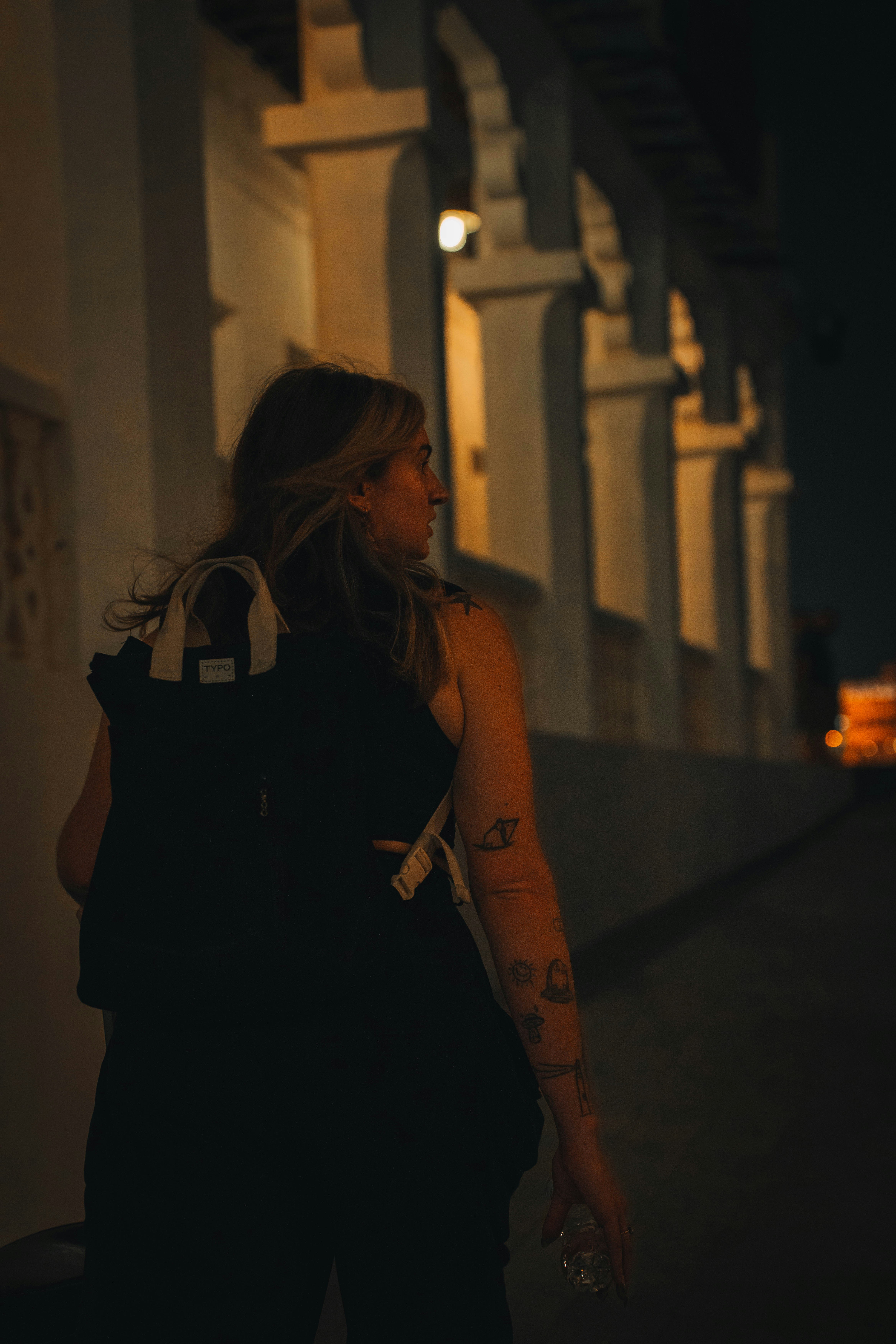 Night Walk: Backlit Stranger Amid Arched Colonnades