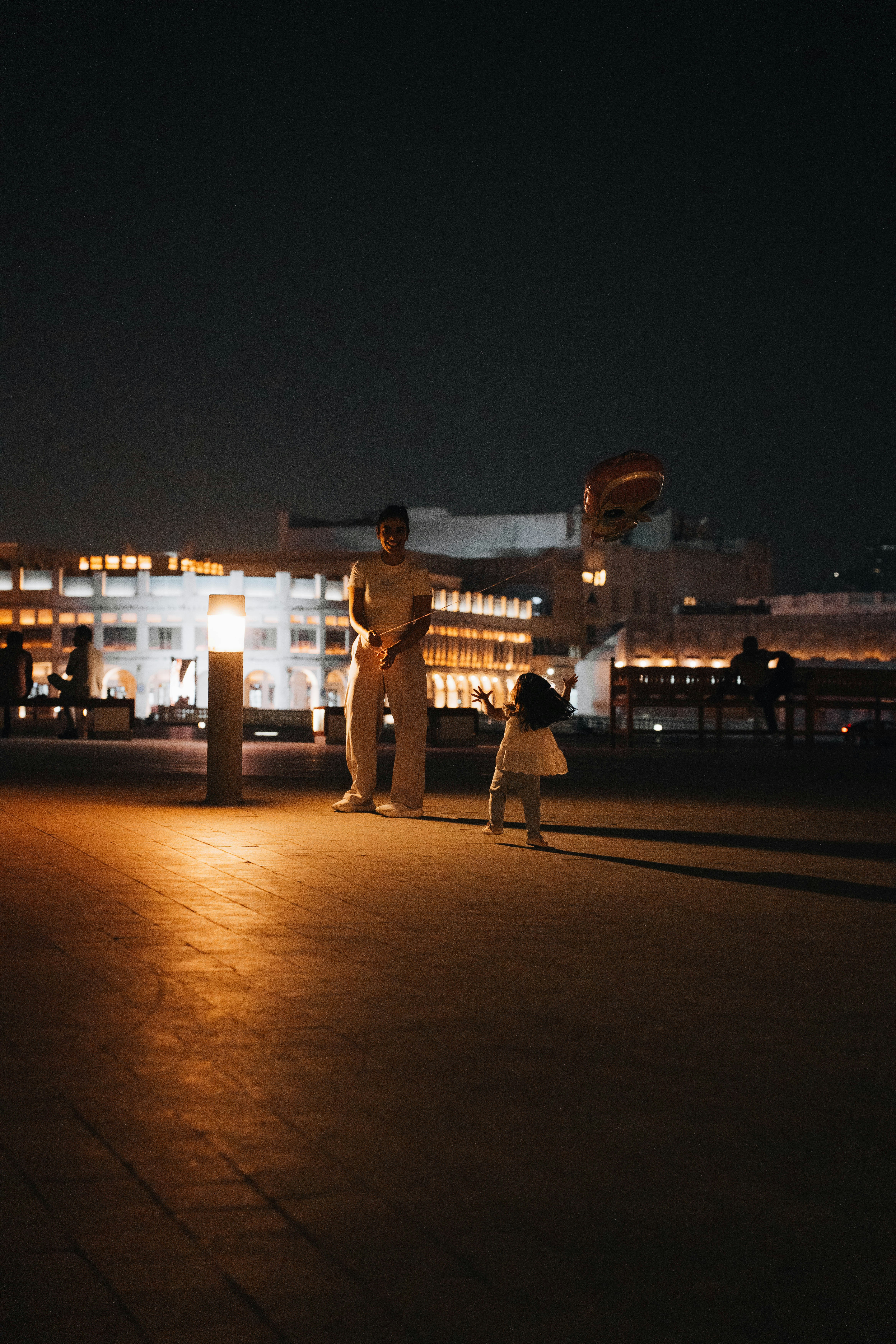 Night Harbor: A Parent and Child Share a Quiet Moment under Warm Streetlight