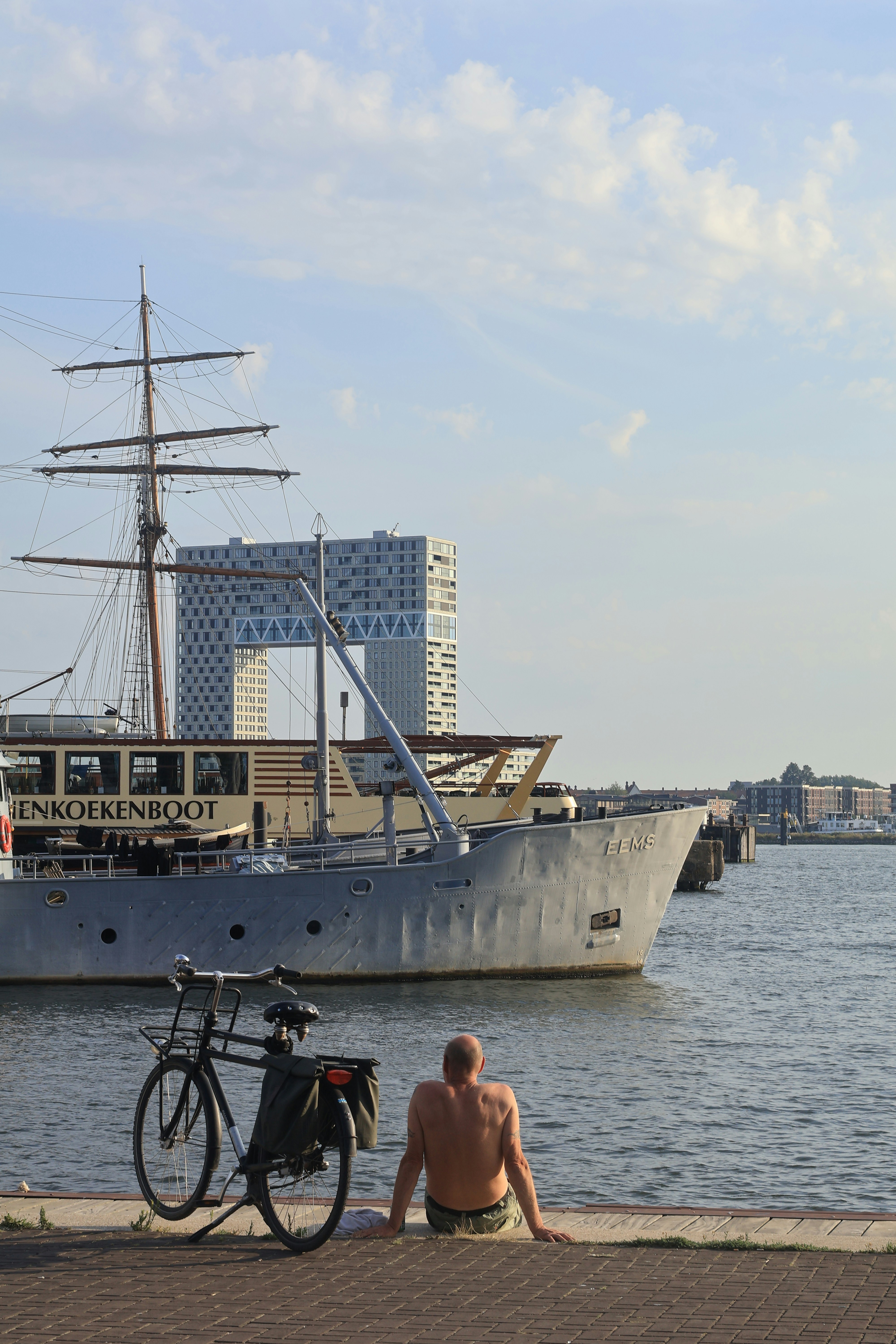 Harbor Quiet: A Figure by the Dock and a Sailboat at Dusk