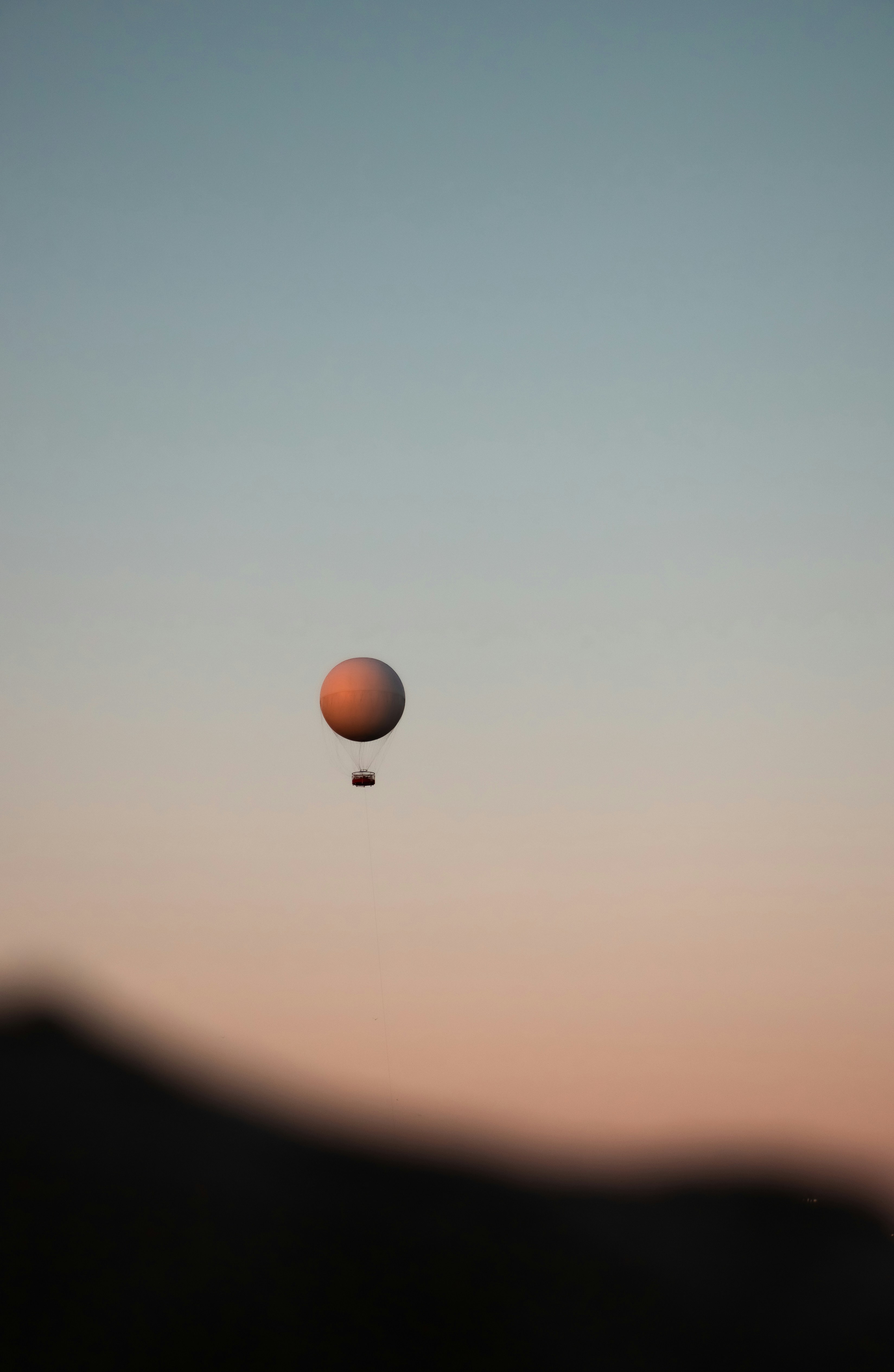 Balloon against the gradient sky: a serene ascent at sunset