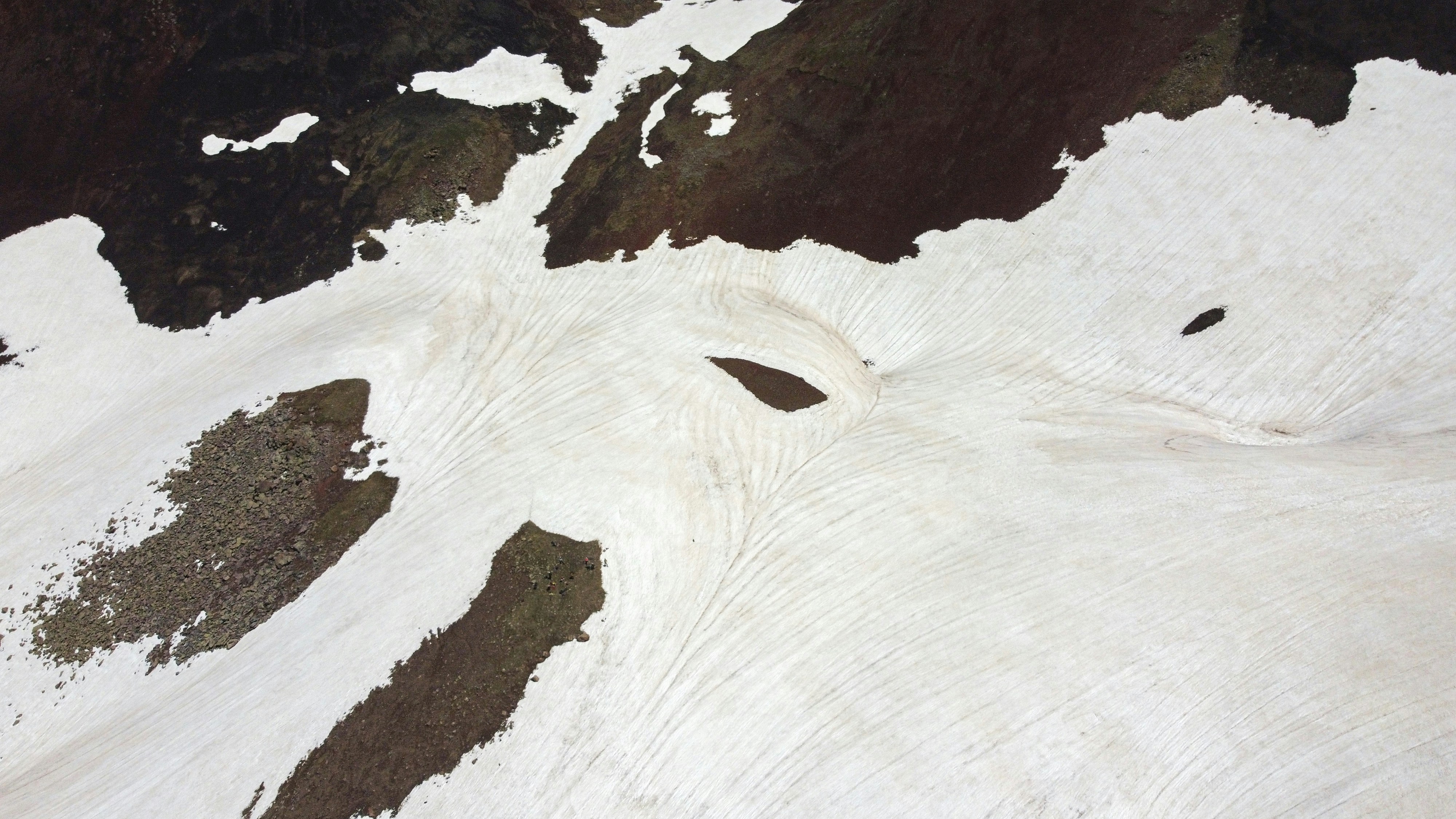Snowfield against rugged volcanic rock: a high-altitude landscape under stark light