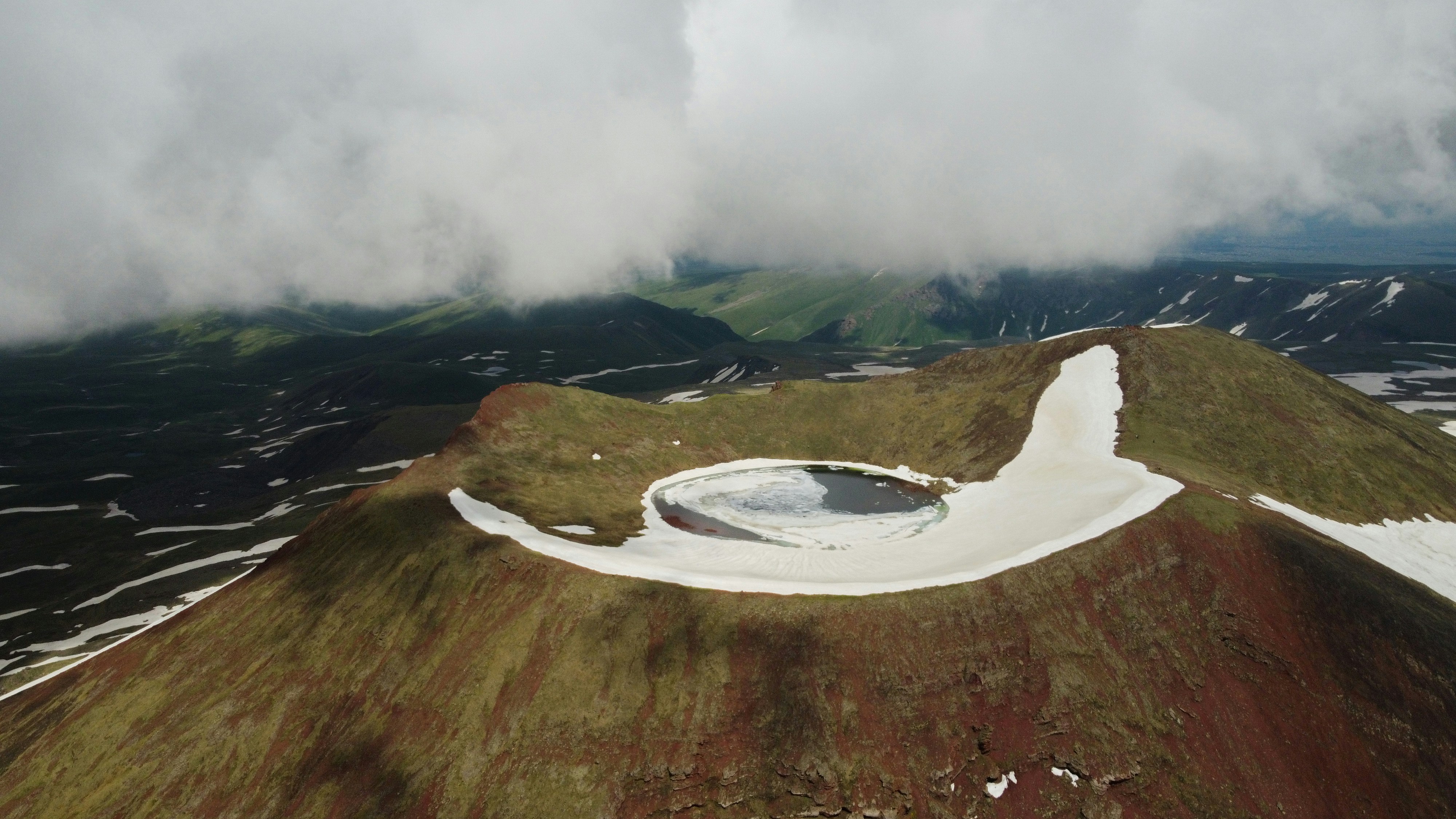 Aerial View of a Snow-ringed Crater on Wind-swept Highlands