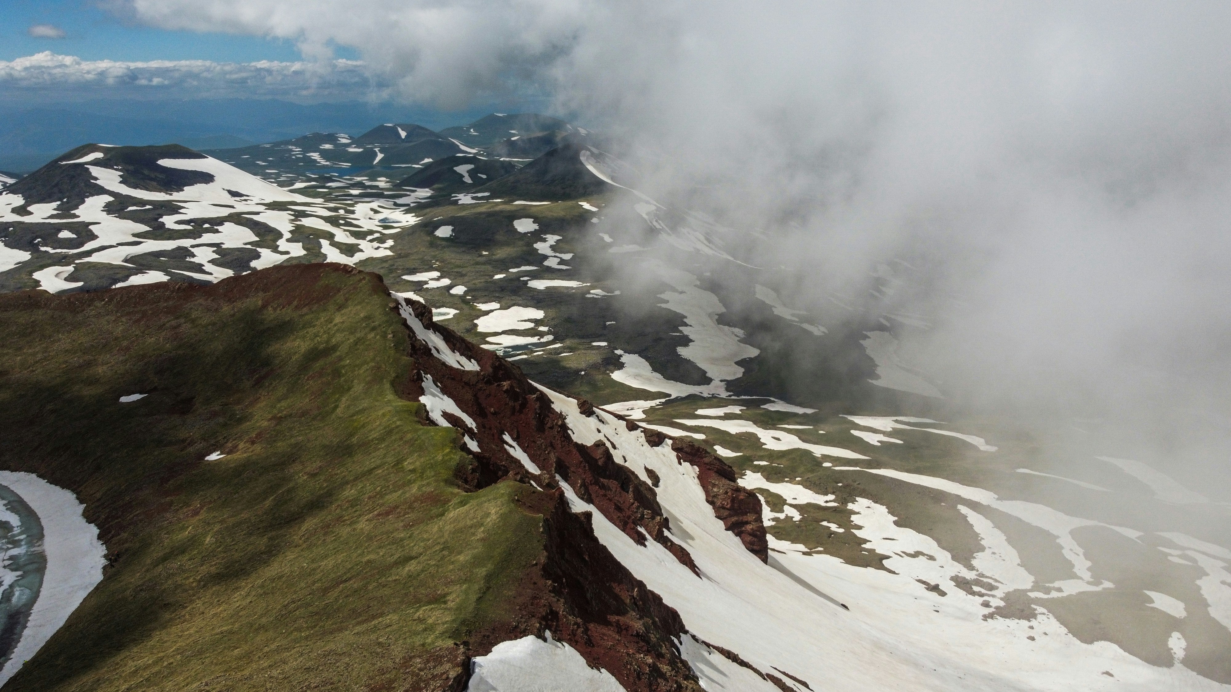 Snow-veiled ridges under drifting clouds over alpine terrain