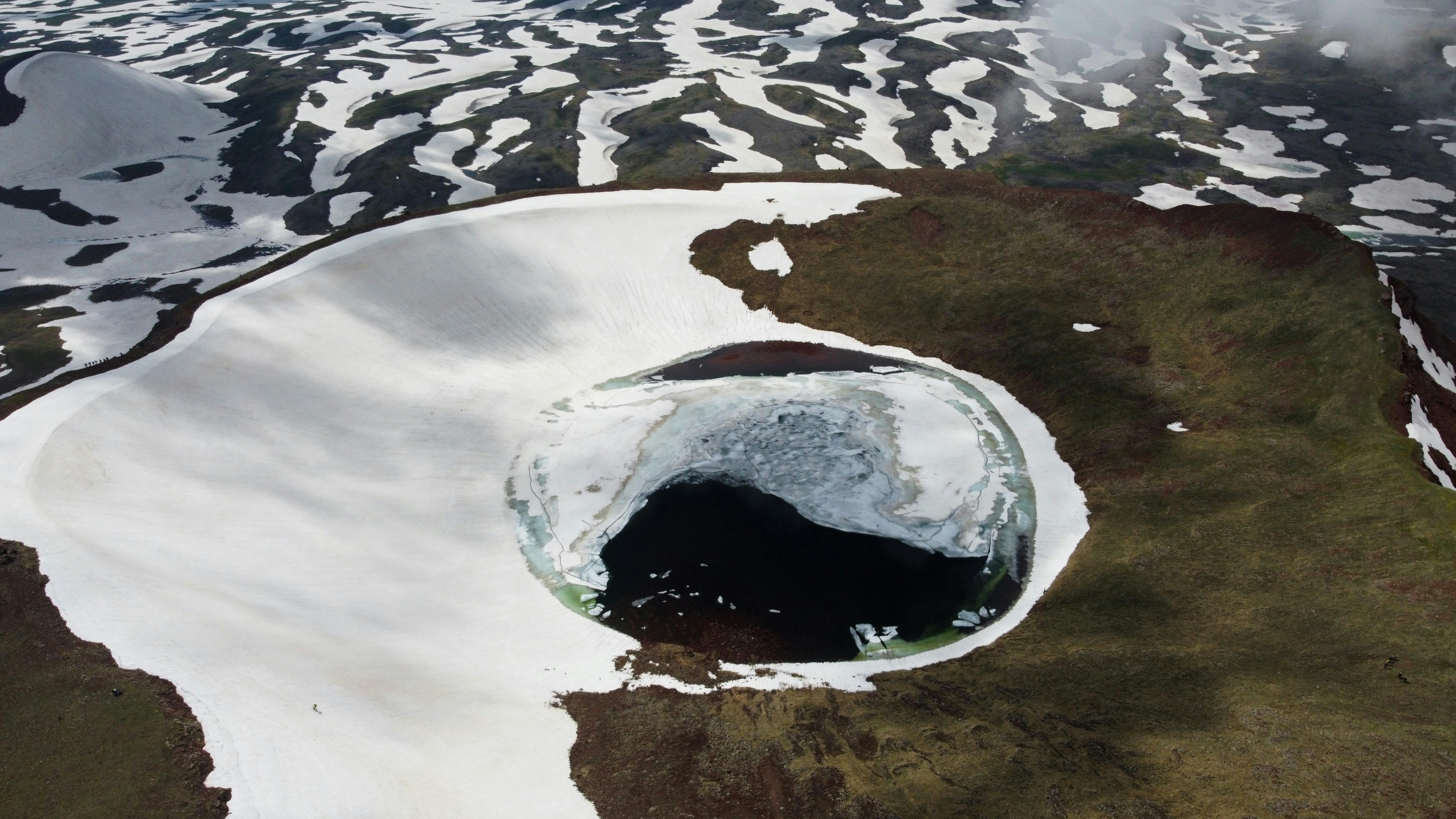 Snow-ringed Hole: a frozen shoreline with a circular snow cave