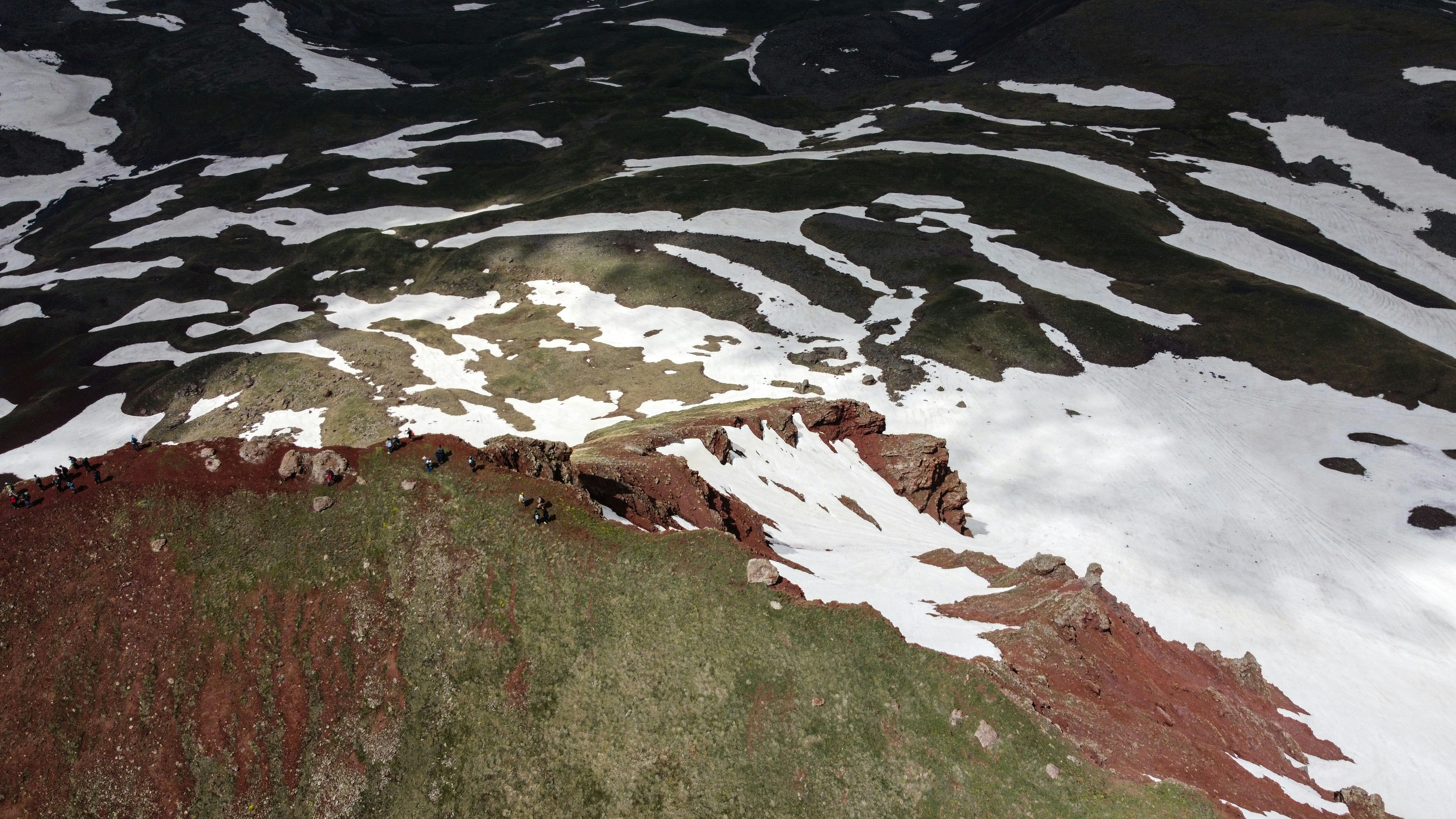 Snow-kissed ridge over a mossy cliff under a sullen sky