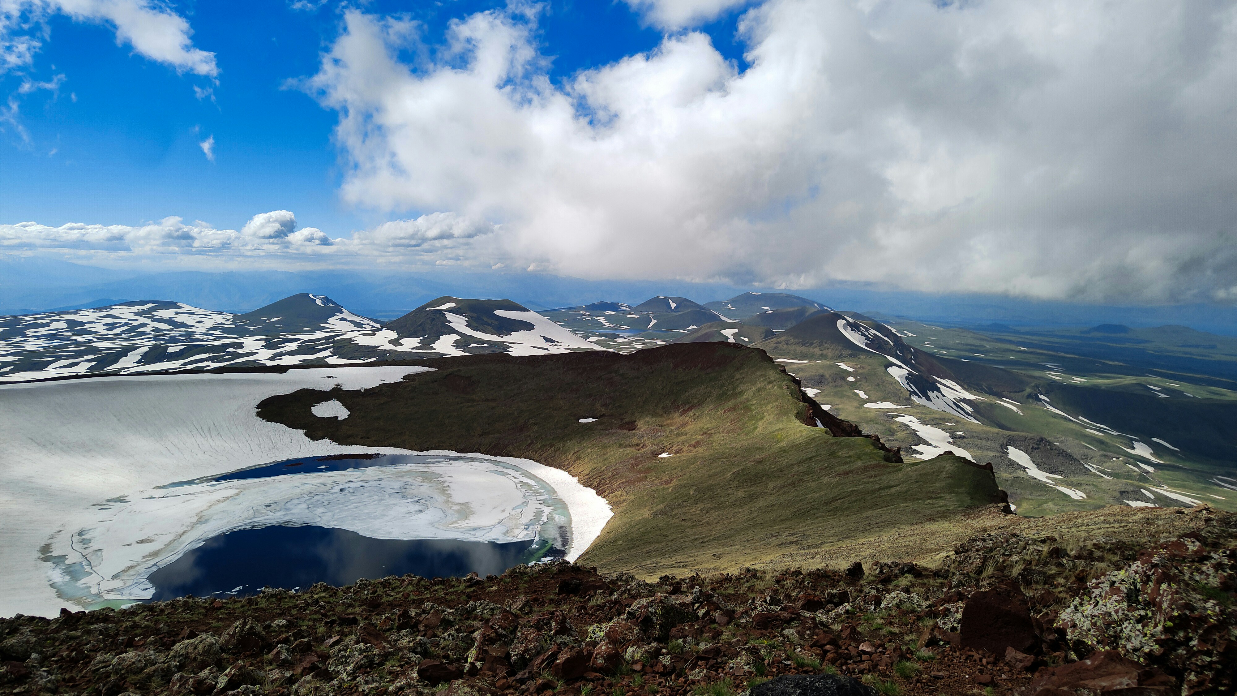 Snowfields on a Rim: A Glacial Plateau Beneath Rolling Clouds