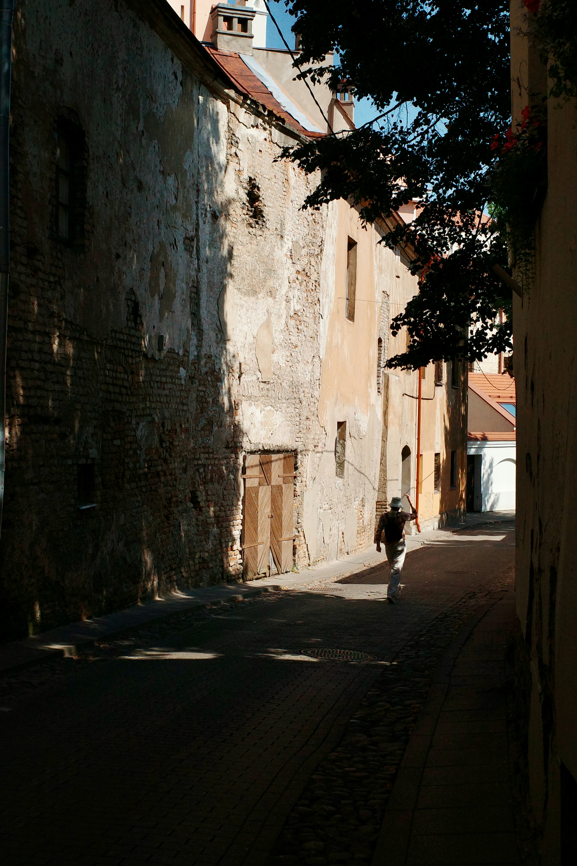 Sunlit Passage: A Lone Pedestrian in a Narrow Historic Street