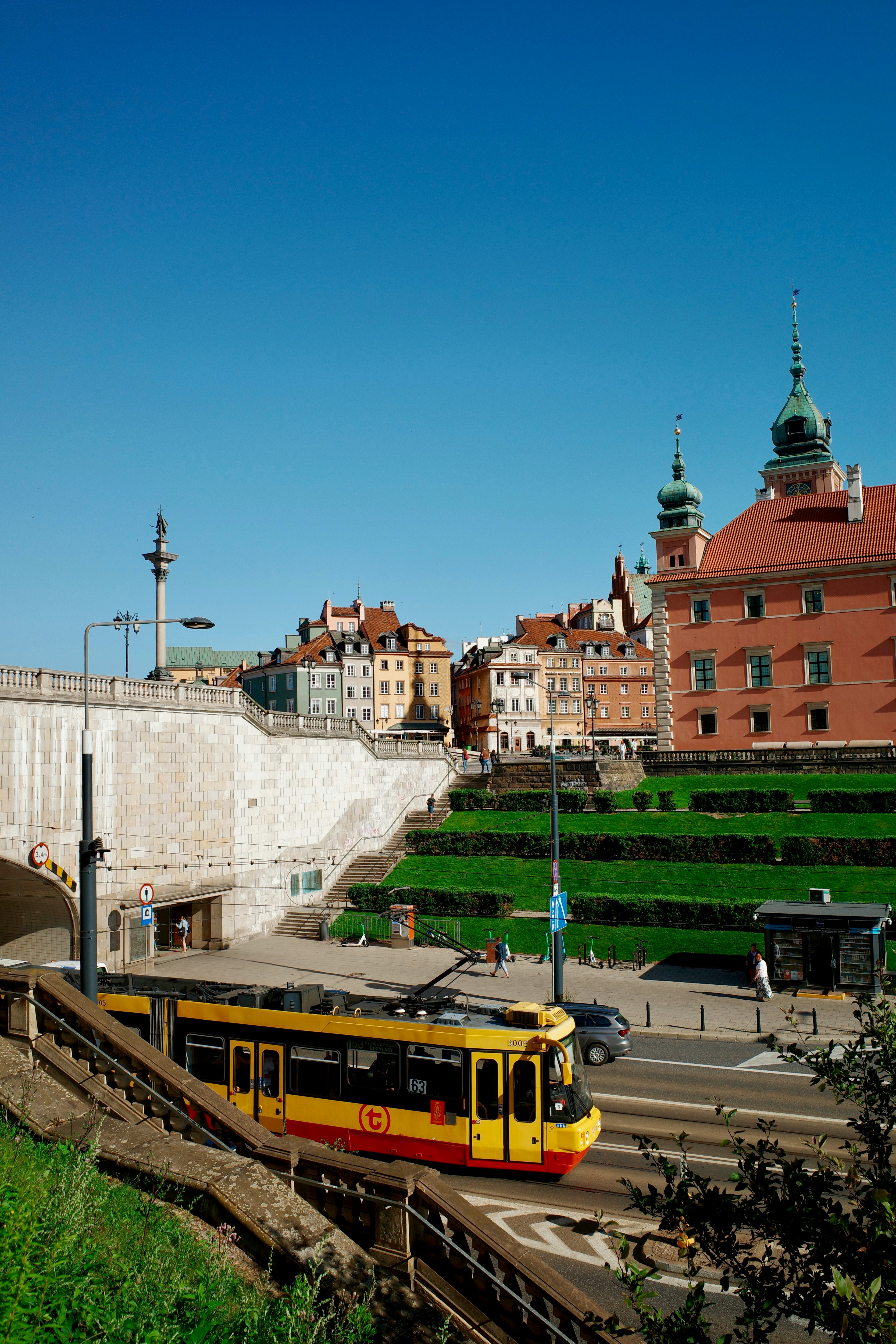 Sunlit tram and terraced cityscape under a clear blue sky