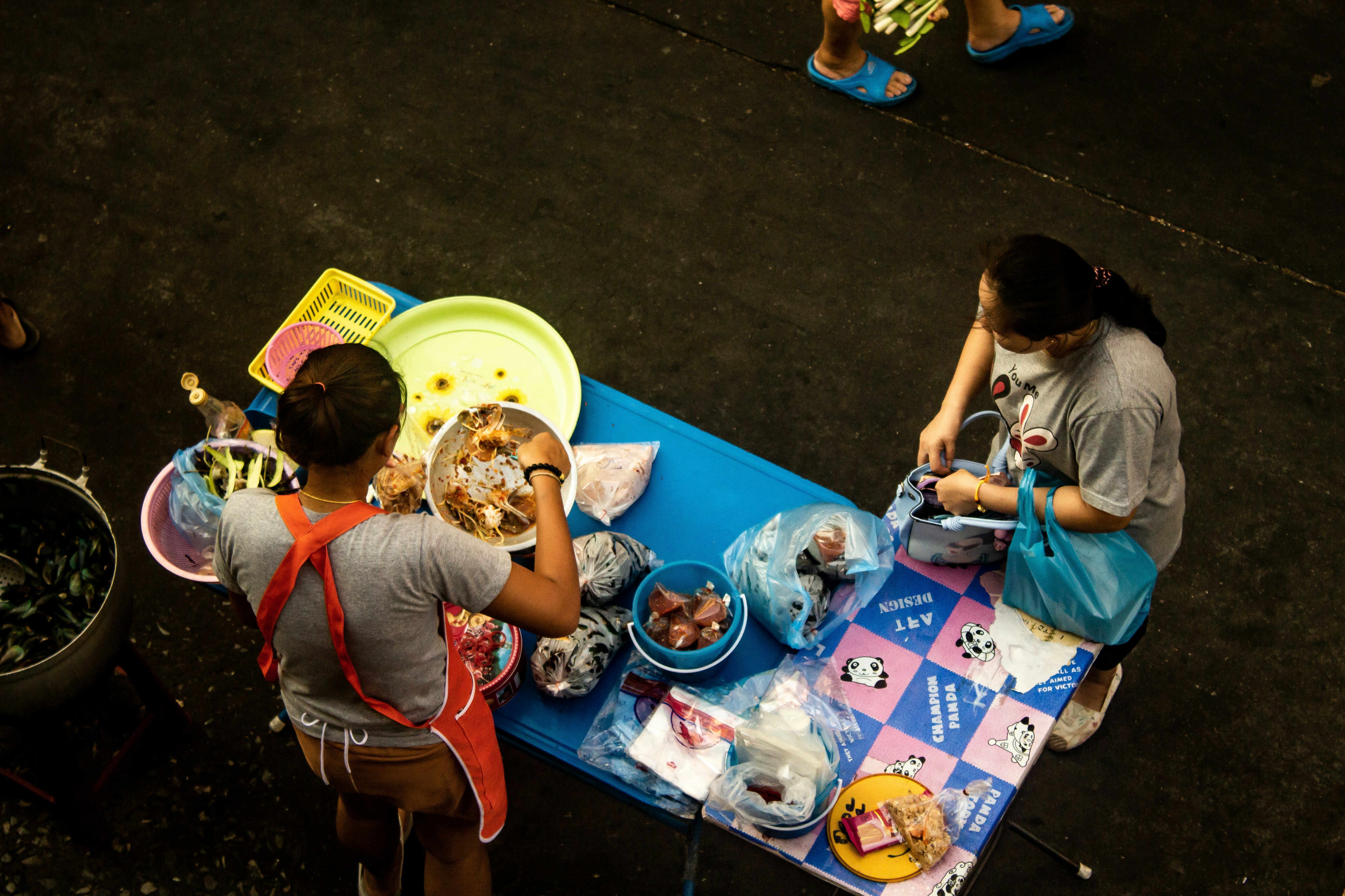 Two street vendors at a food stall share a busy moment on a dark street