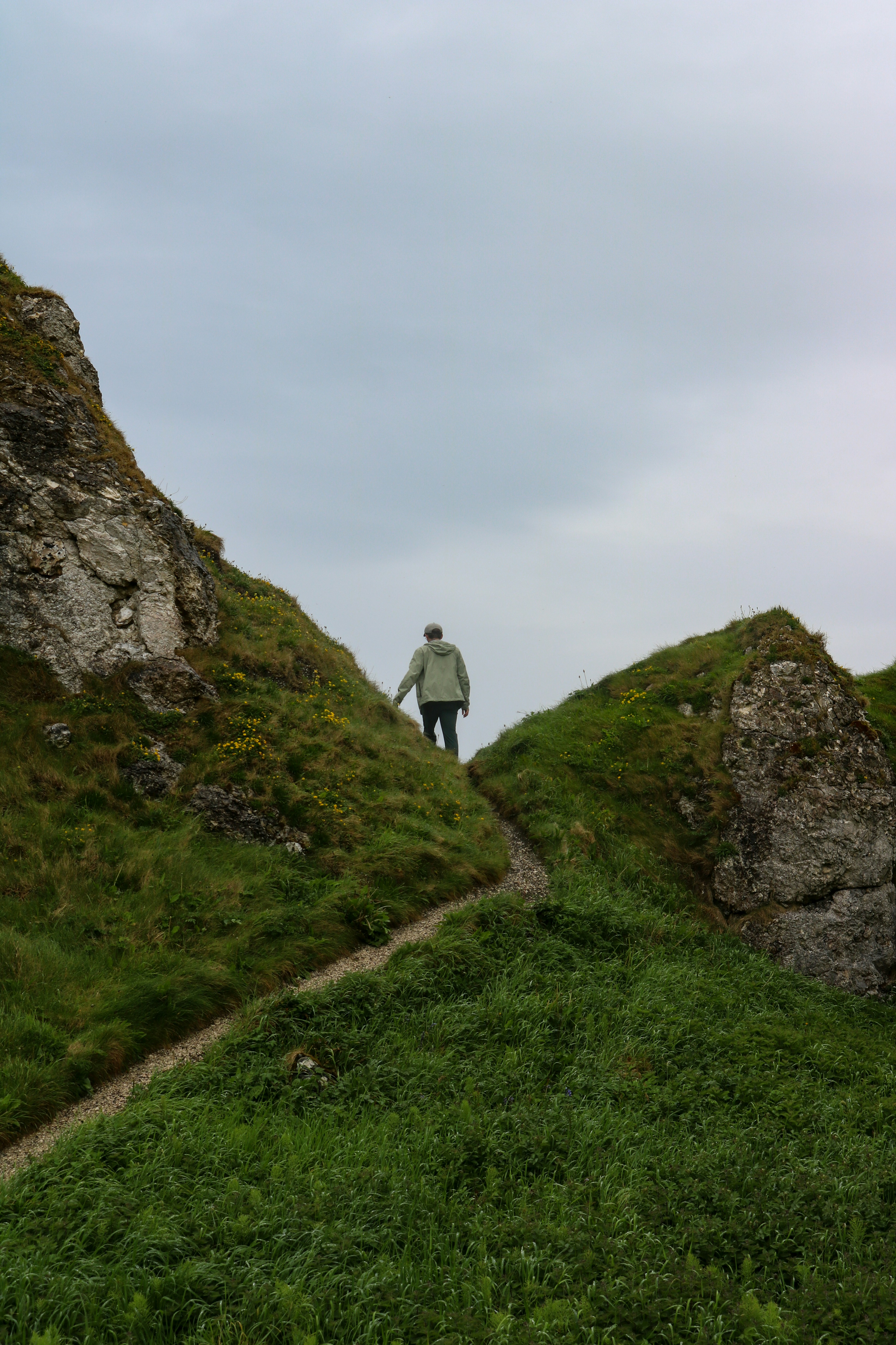 Soaring Path: A solitary walker ascends a grassy ridge between rugged cliffs