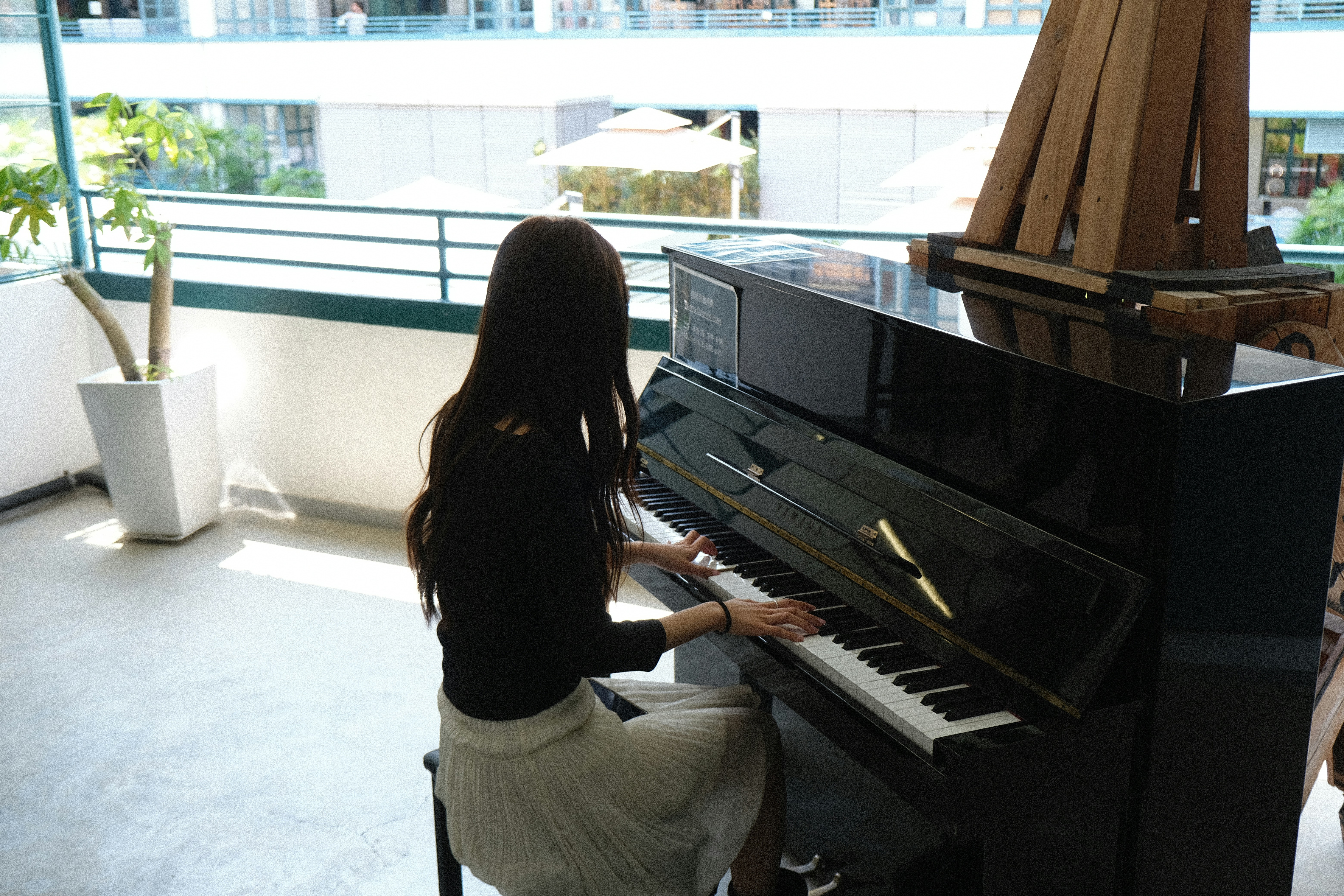Quiet Focus at the Black Grand: A Pianist in a Sunlit Atrium
