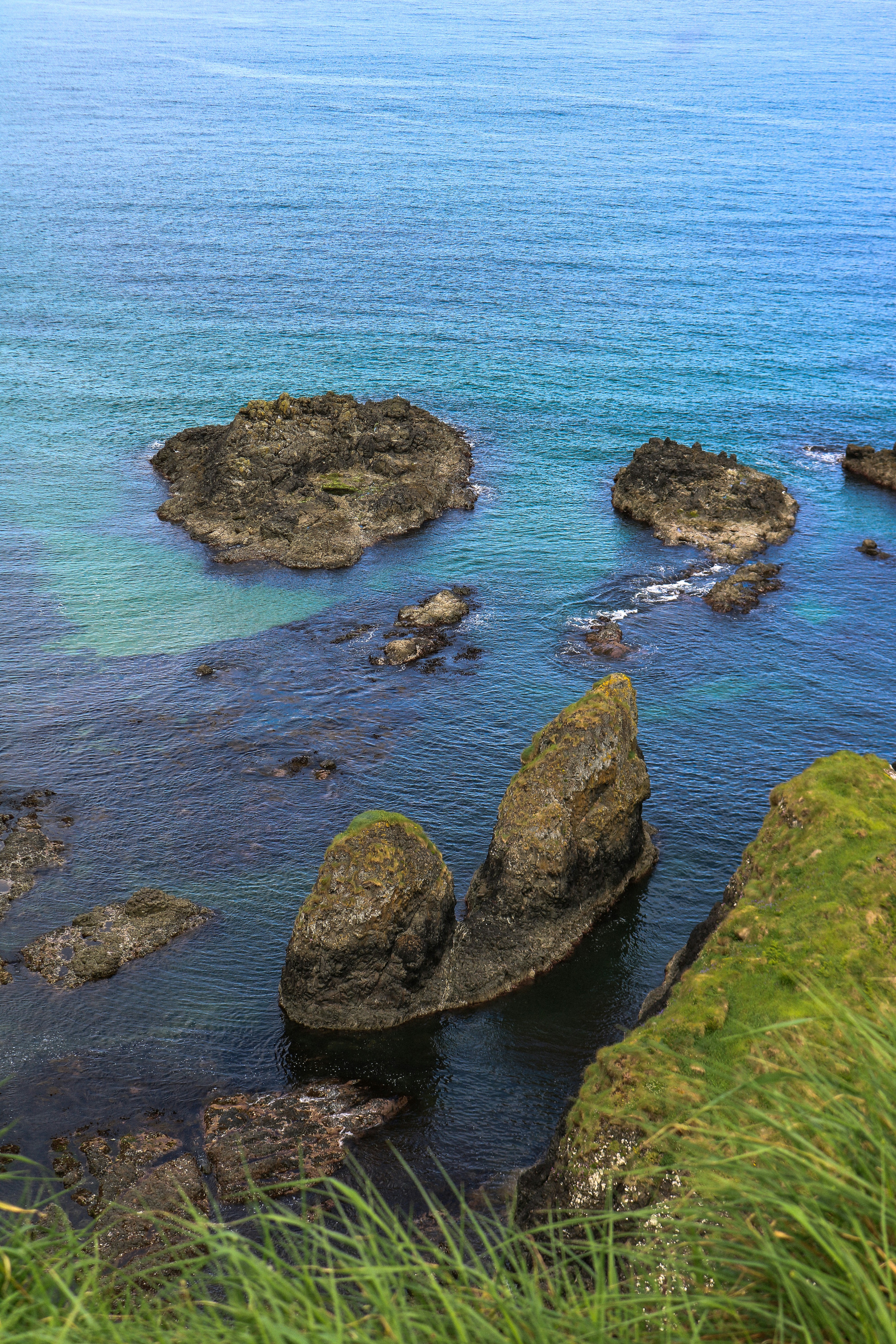 Storm-softened cliffs meet turquoise depths along a quiet shoreline