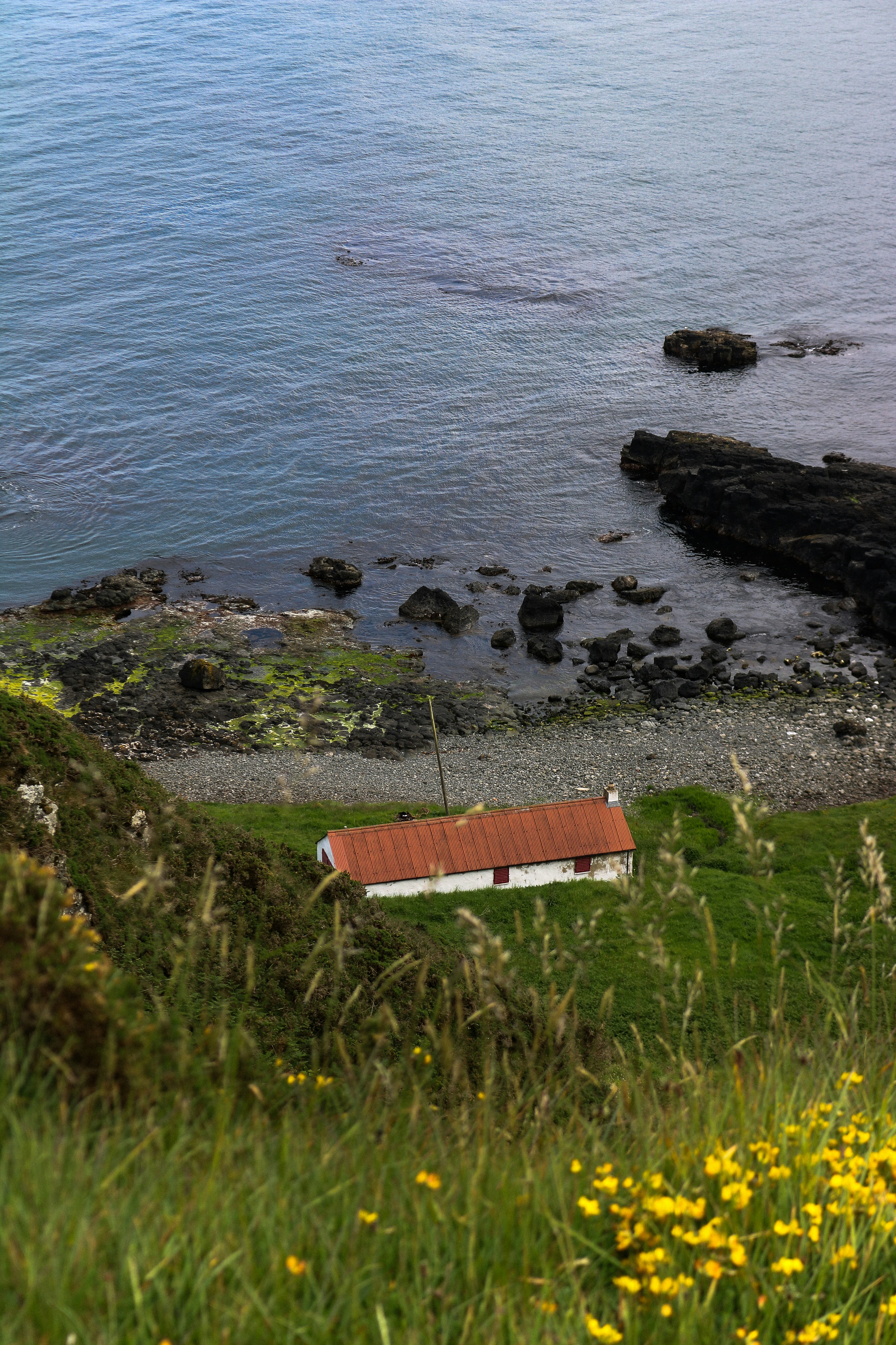 Red-roofed cottage at the edge of a cliff overlooking the sea