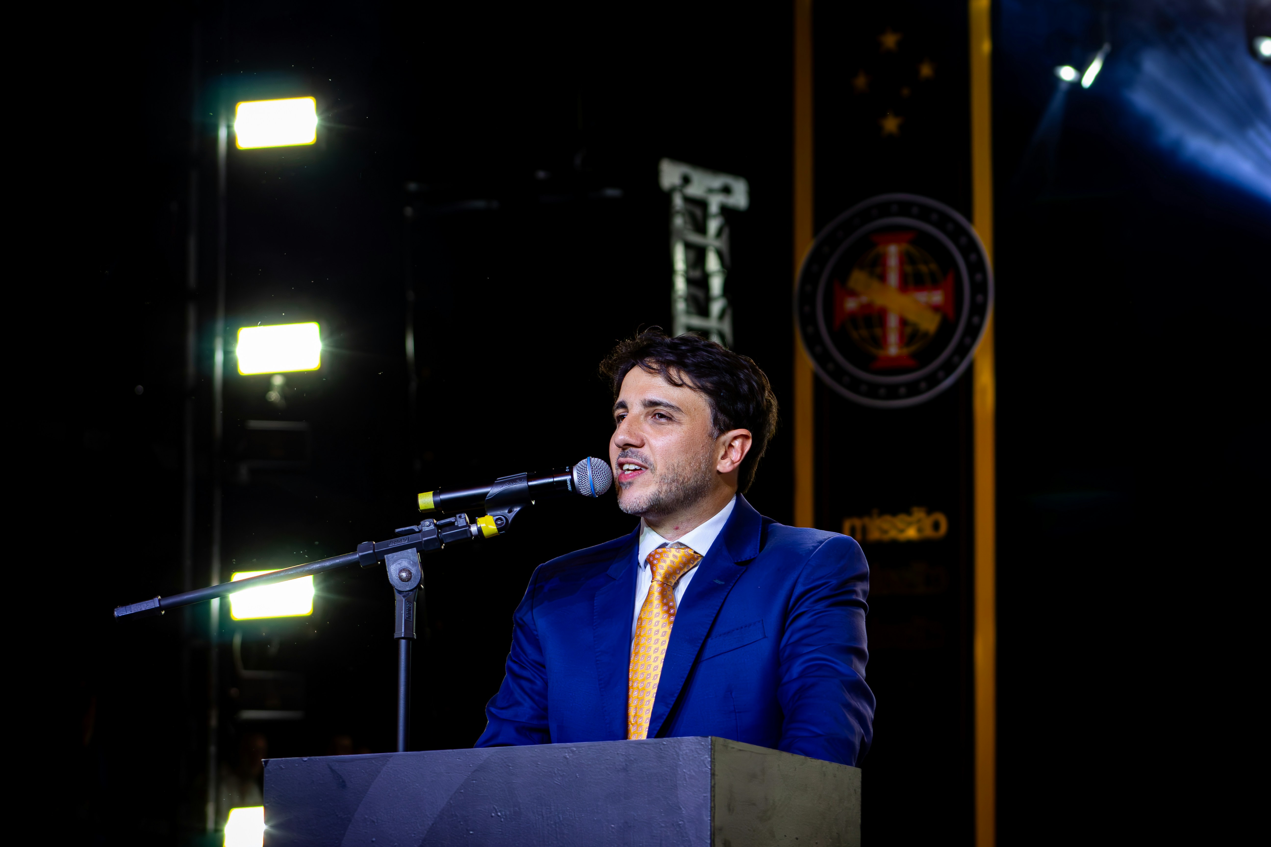 Blue-suited Speaker at the Podium Under Stage Lights