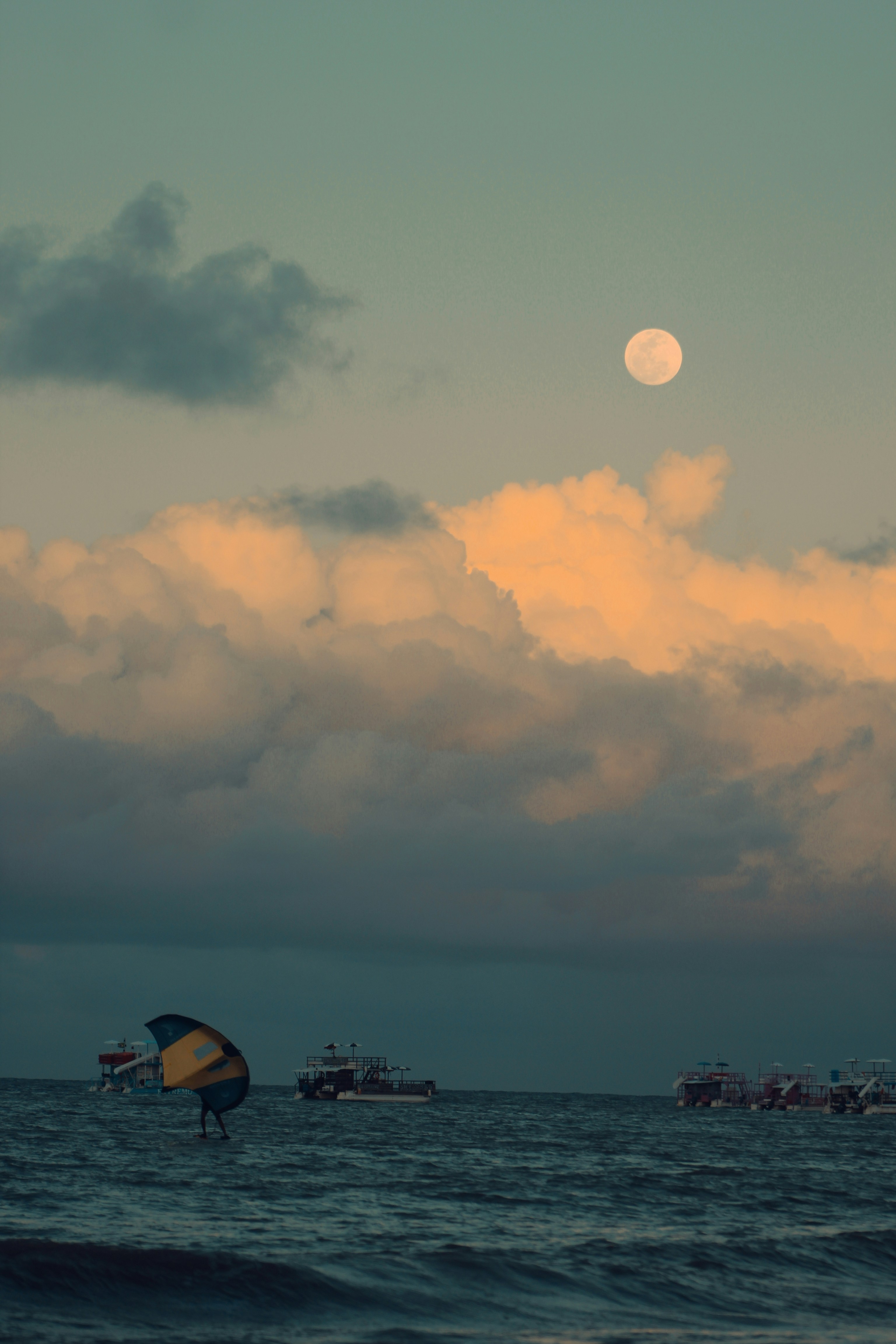 Moonrise Over Quiet Ocean: A Dusk Portrait of a Seafront Scene with Kite Surfer