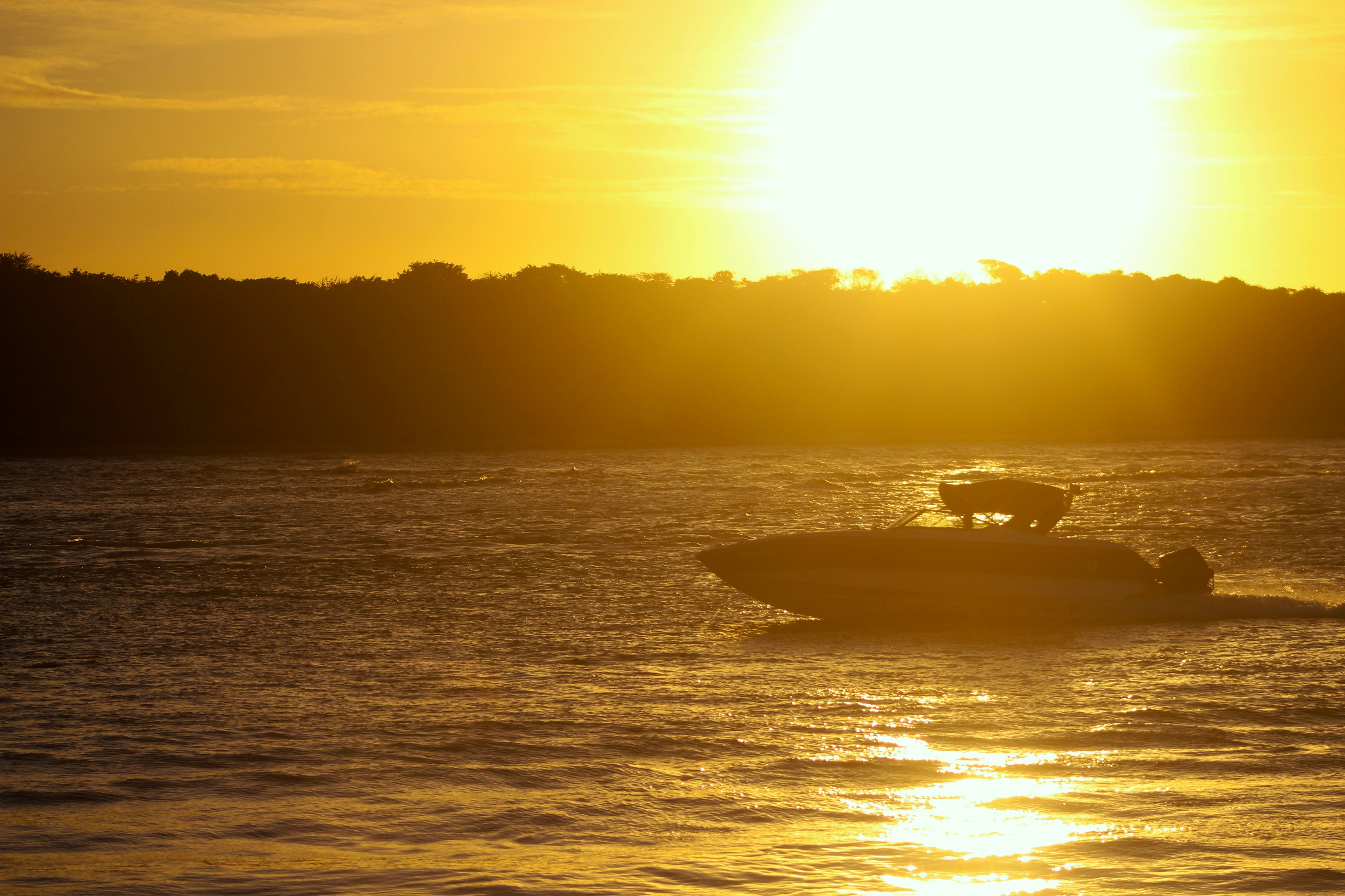 Golden Bow on the Horizon: Boat Silhouette at Sunset