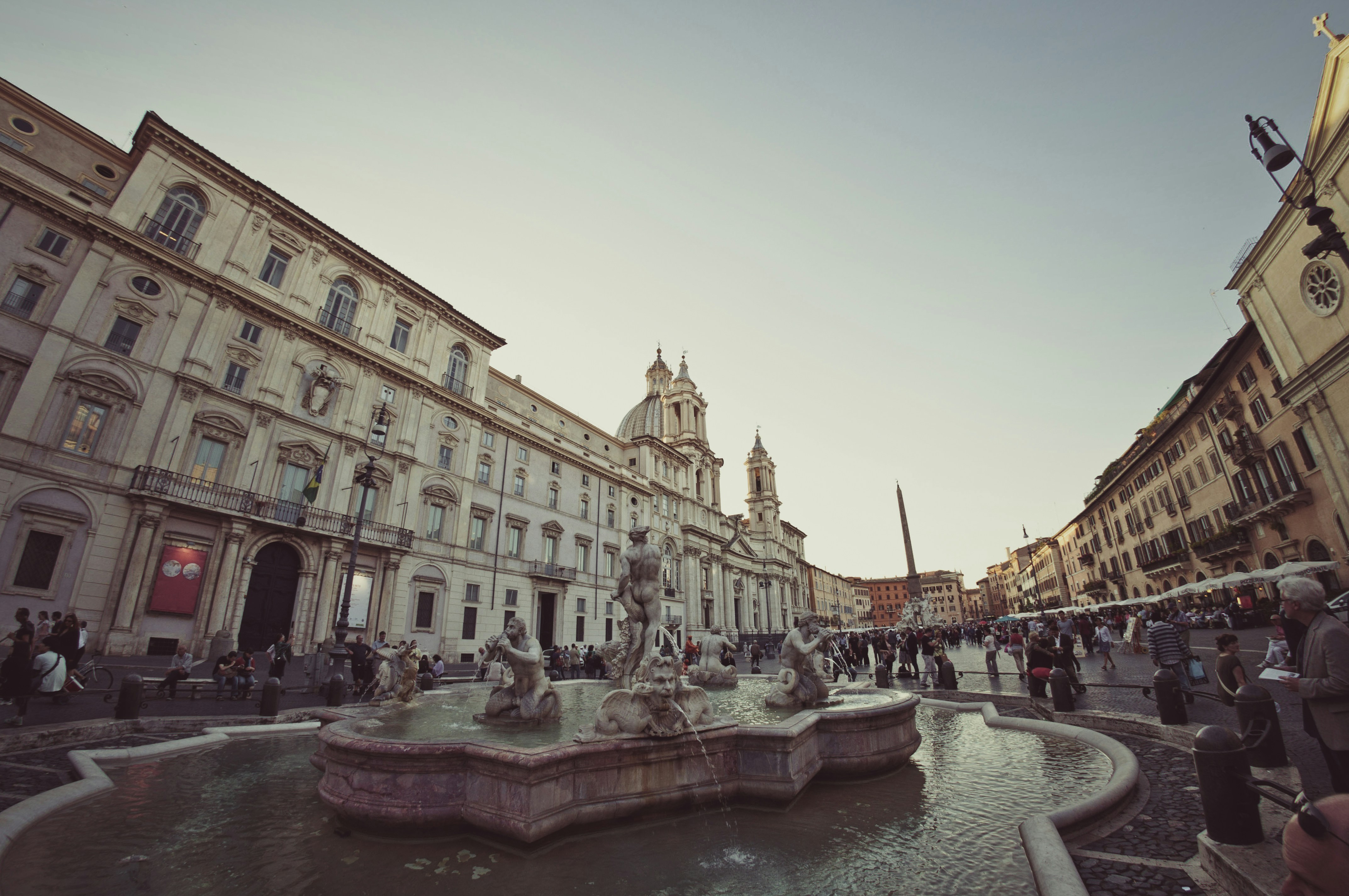 Stone Sunlit Piazza: Fountains, Statues, and a Cathedral Crest