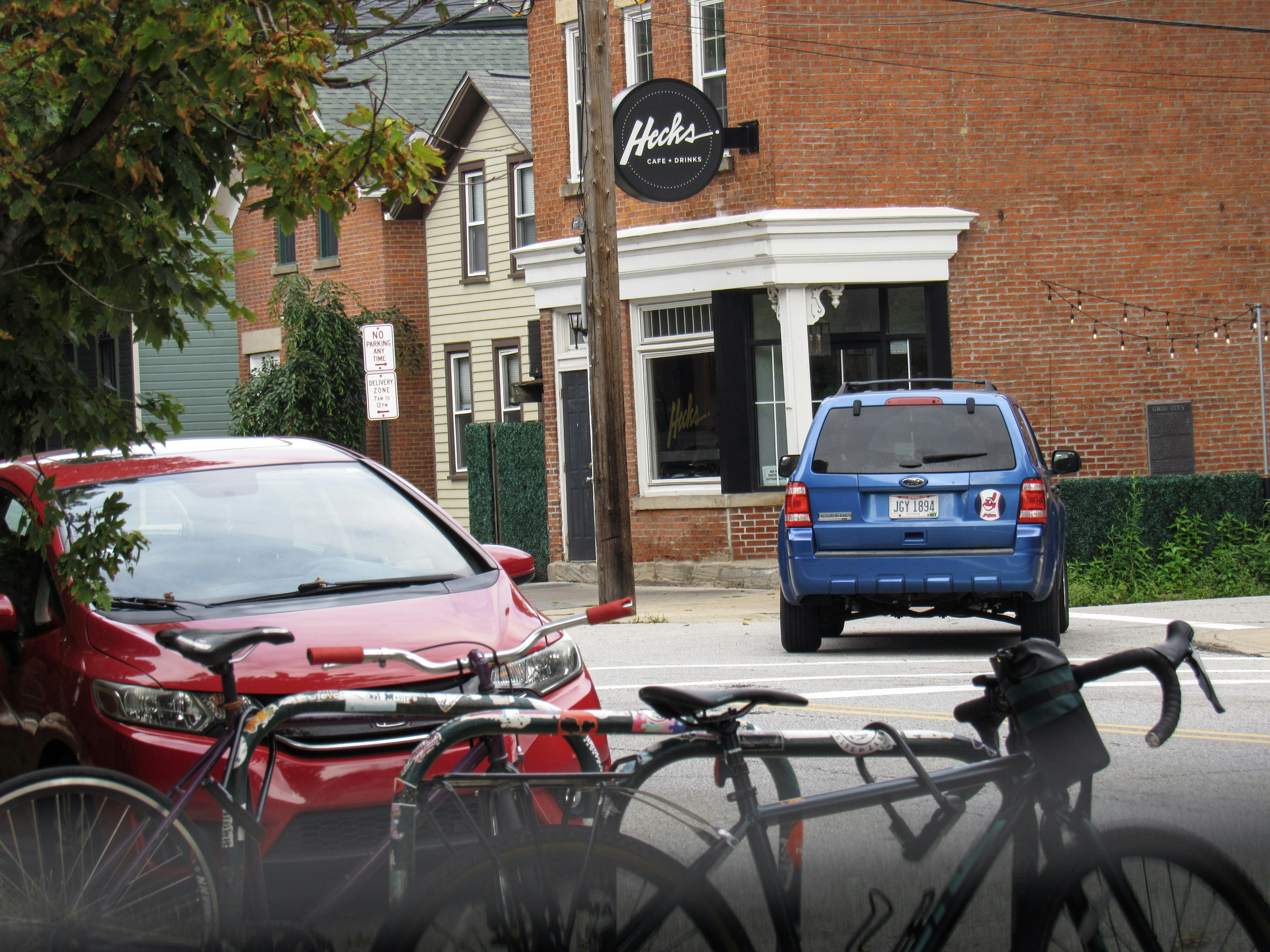 Red Car, Blue SUV, and Bicycles on a Quiet Urban Street