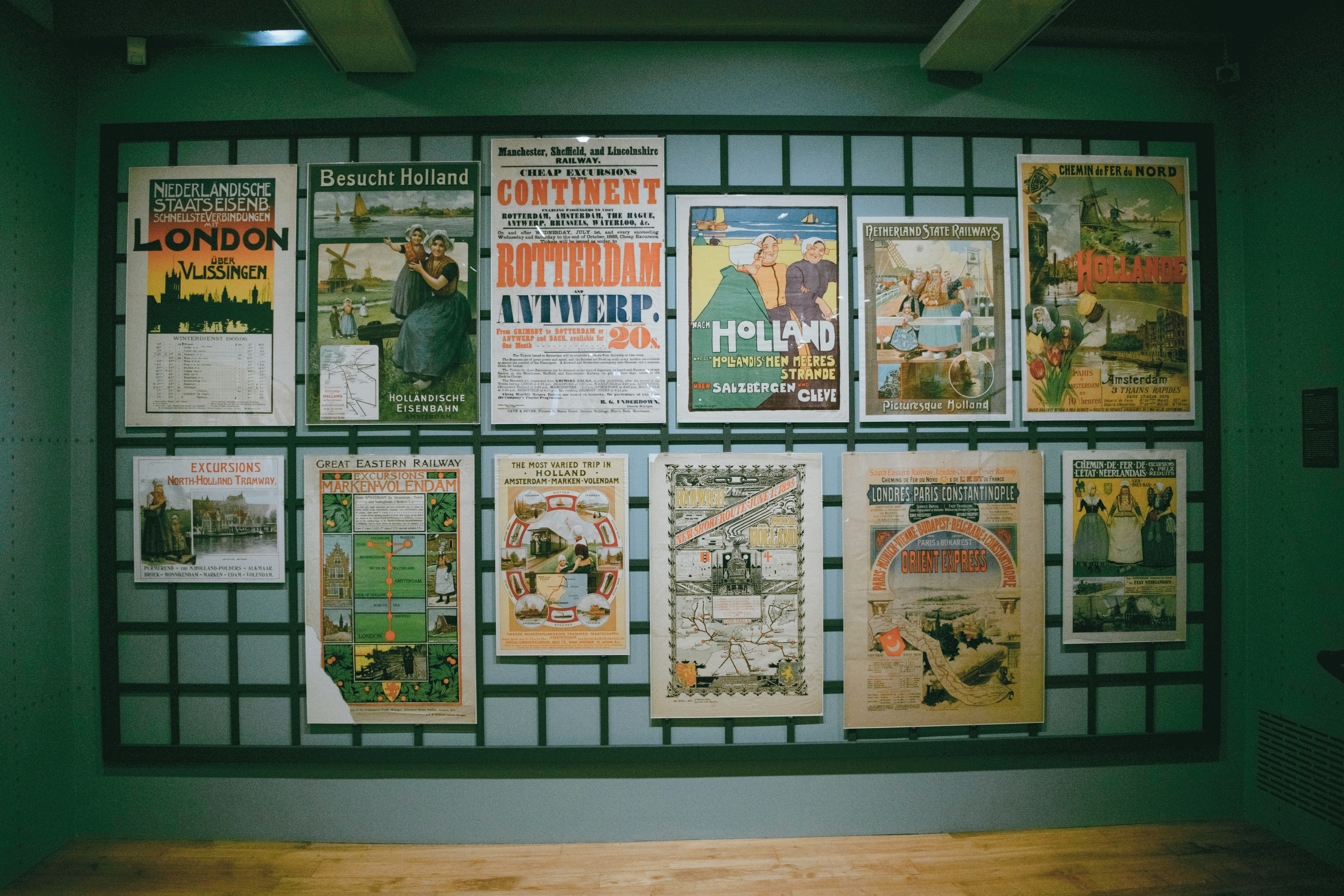 Poster Grid on a Green Wall: Travel Advertisements Framed