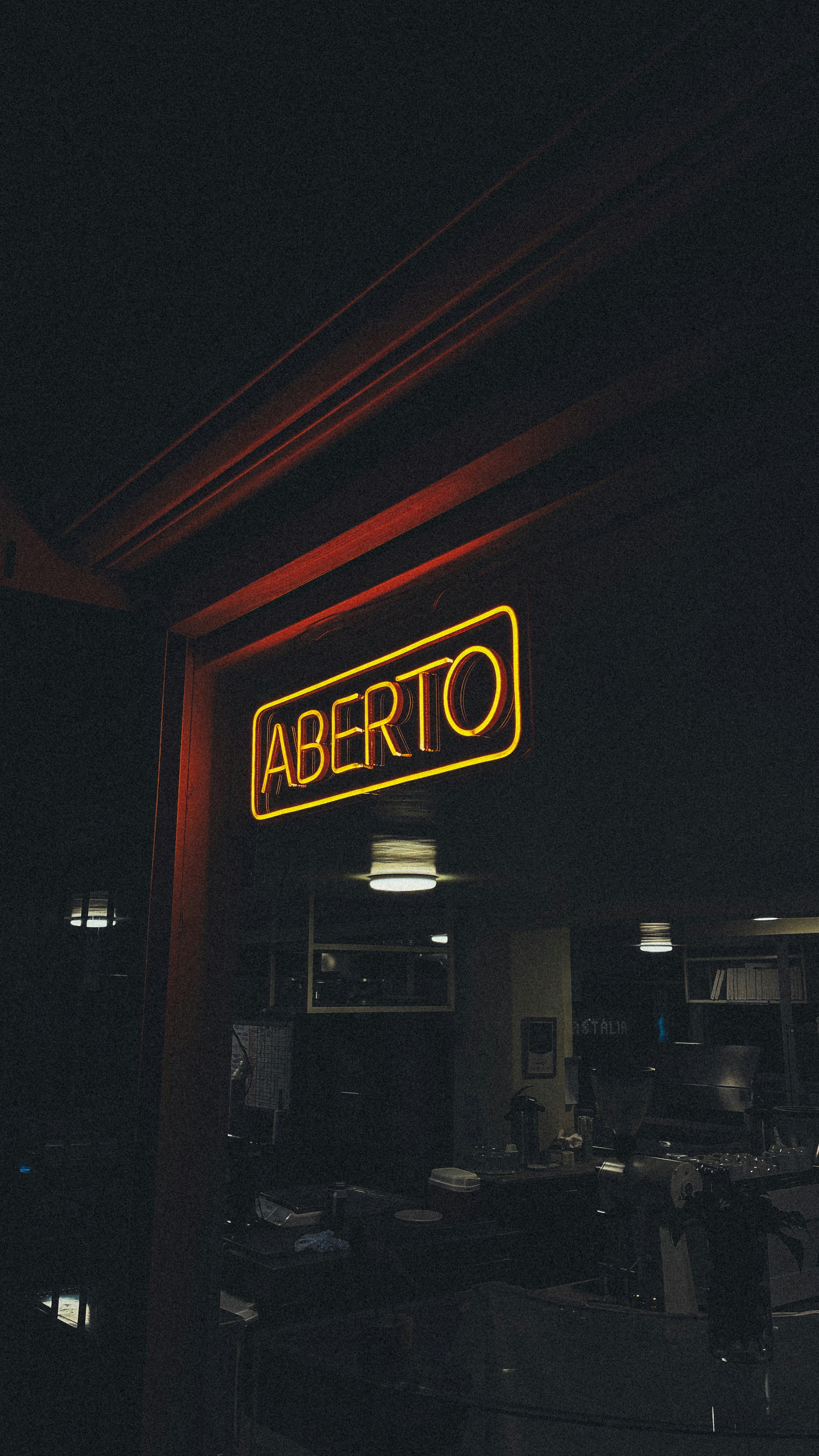 Neon OPEN sign casting a warm glow on a quiet storefront at night