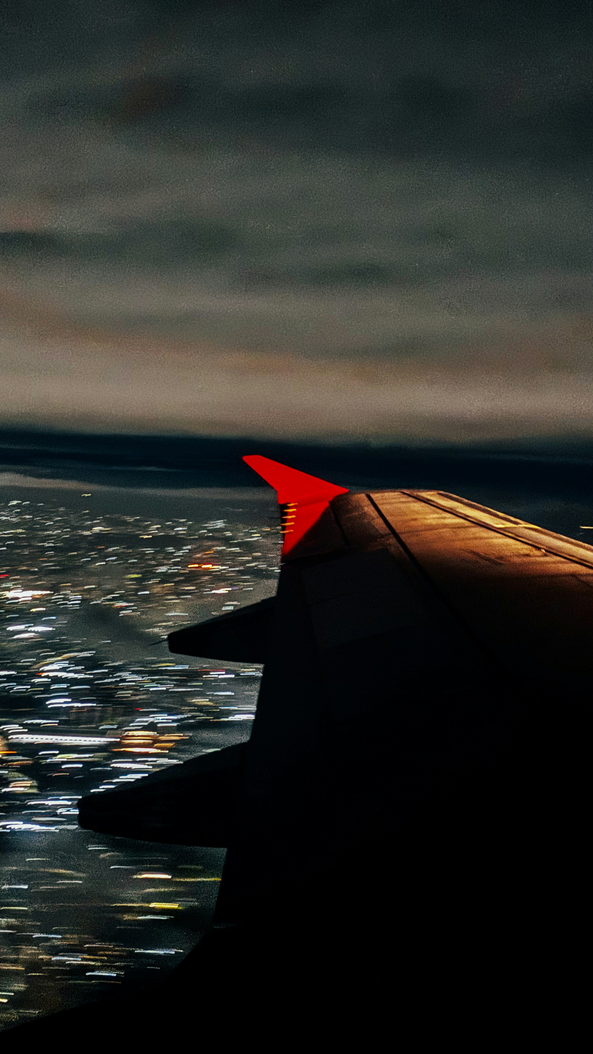 High Altitude Wing: City Lights Beneath a Red-Tipped Winglet