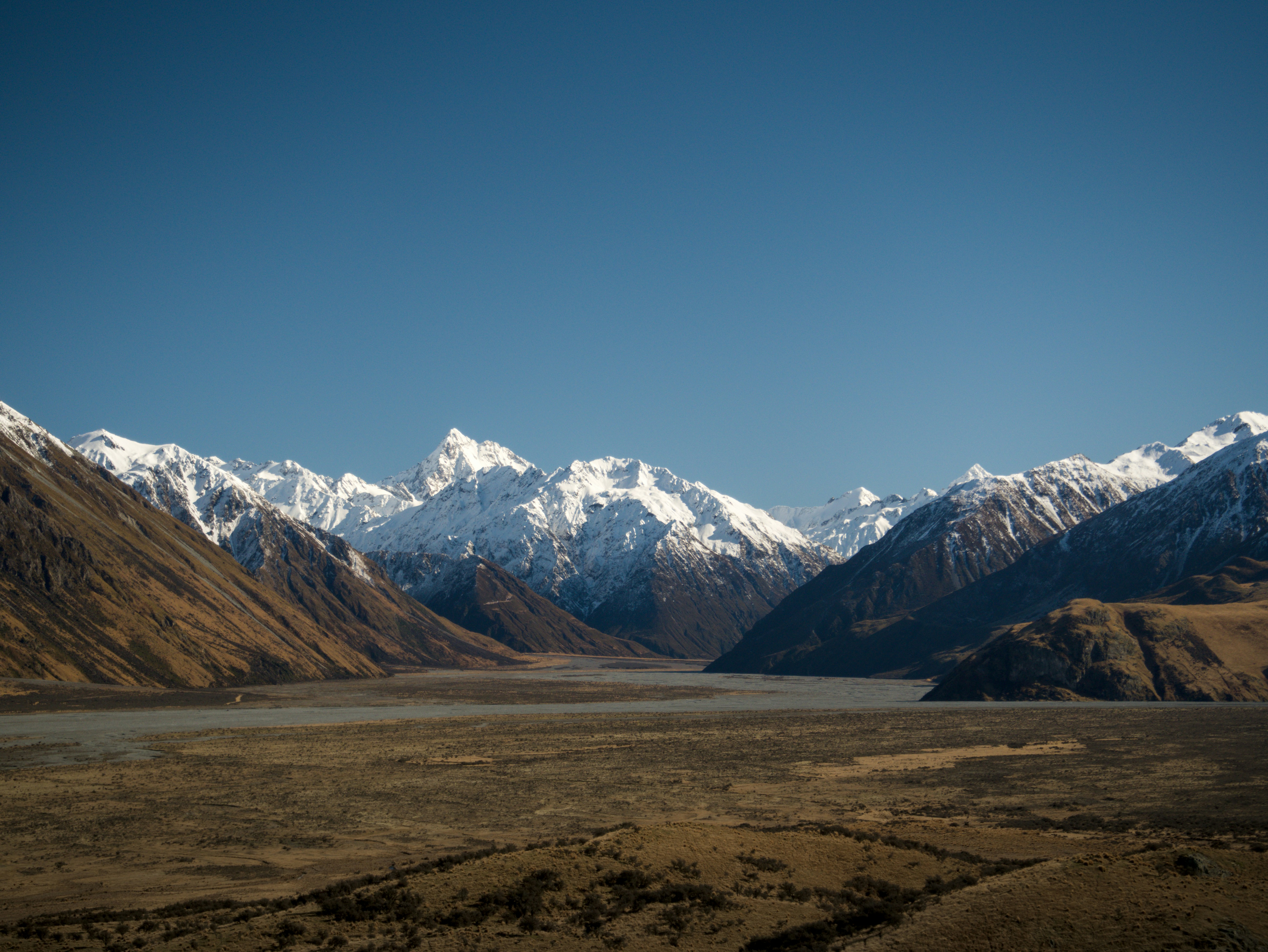 Snow-kissed valley and alpine silhouettes under a clear blue dome
