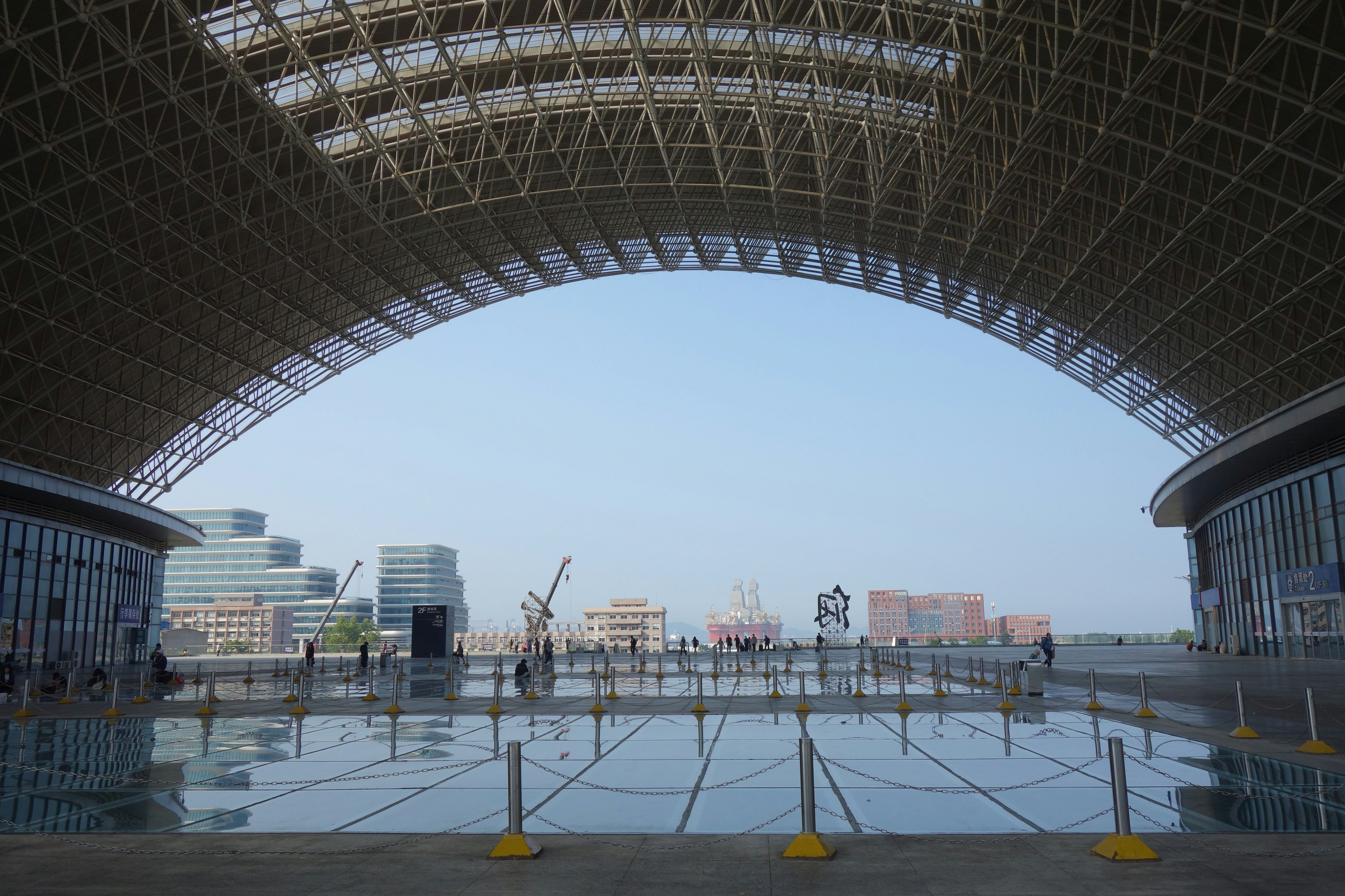 Curved Roof, Open Atrium: Industrial Archway Framed by Waterfront skyline