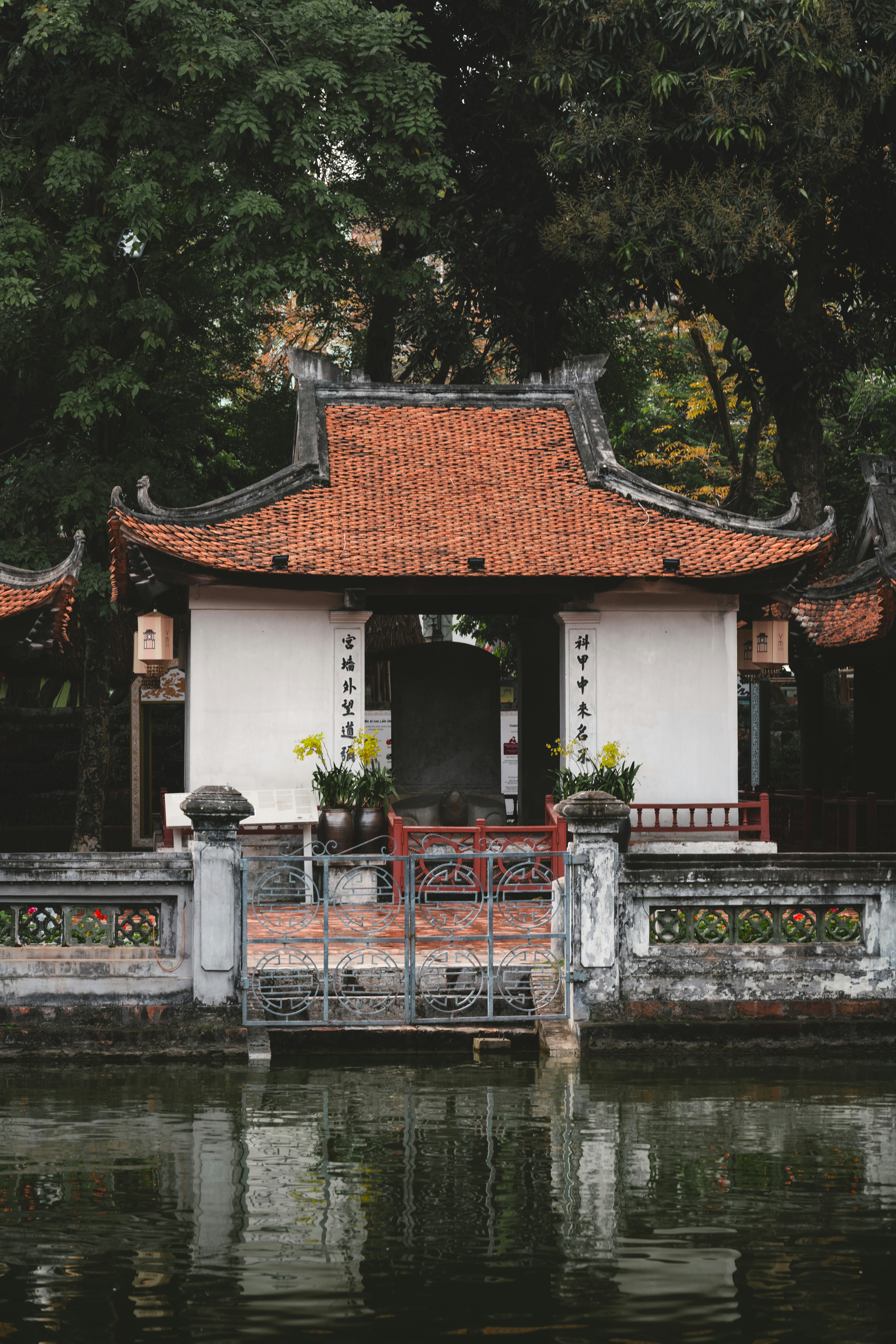 Temple by the Canal: Red Tiled Gate Framed by Water and Trees