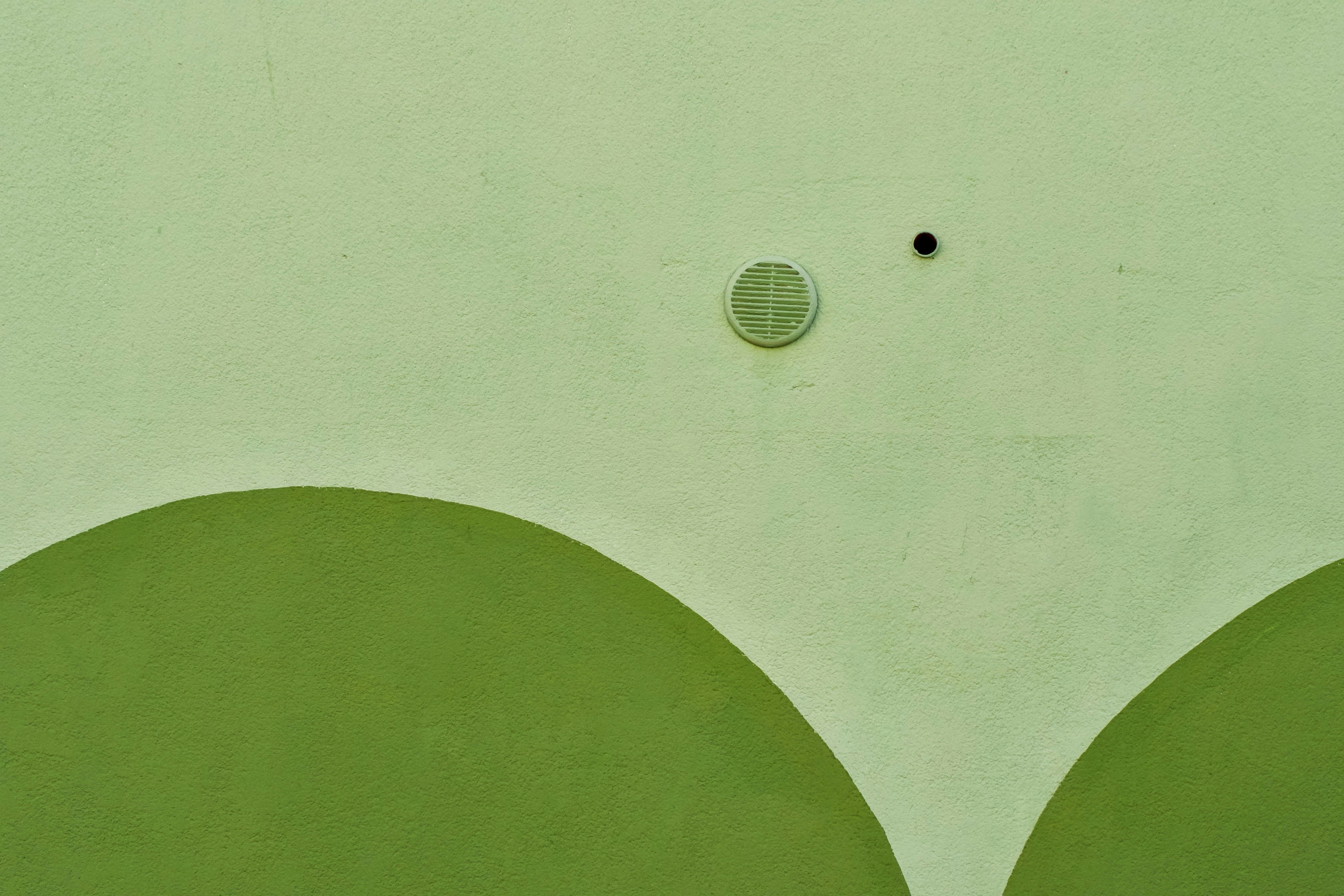 Two emerald arcs meet beneath a pale green wall