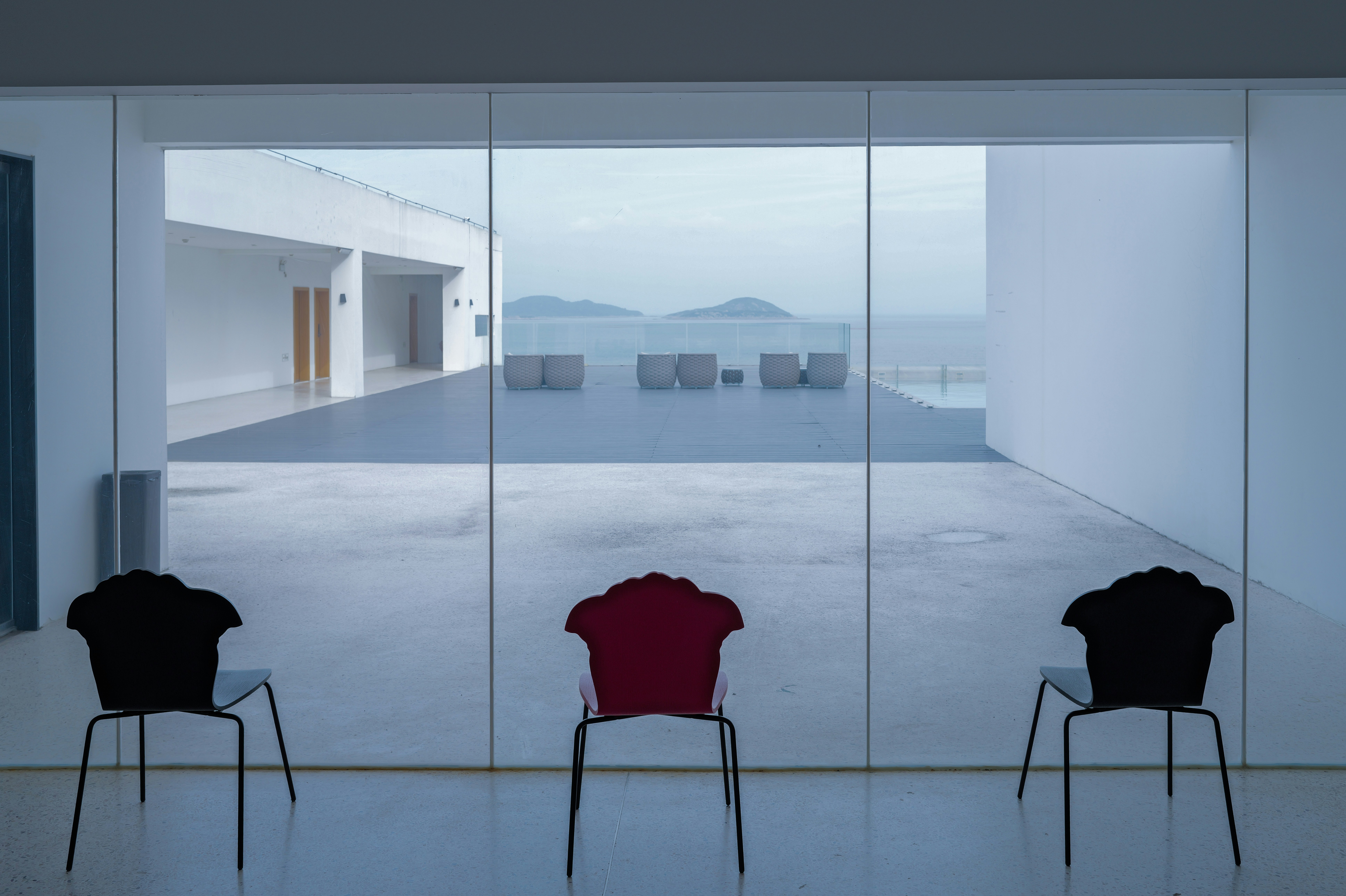 Symmetry and Silence: Three Chairs Facing a Tranquil Ocean