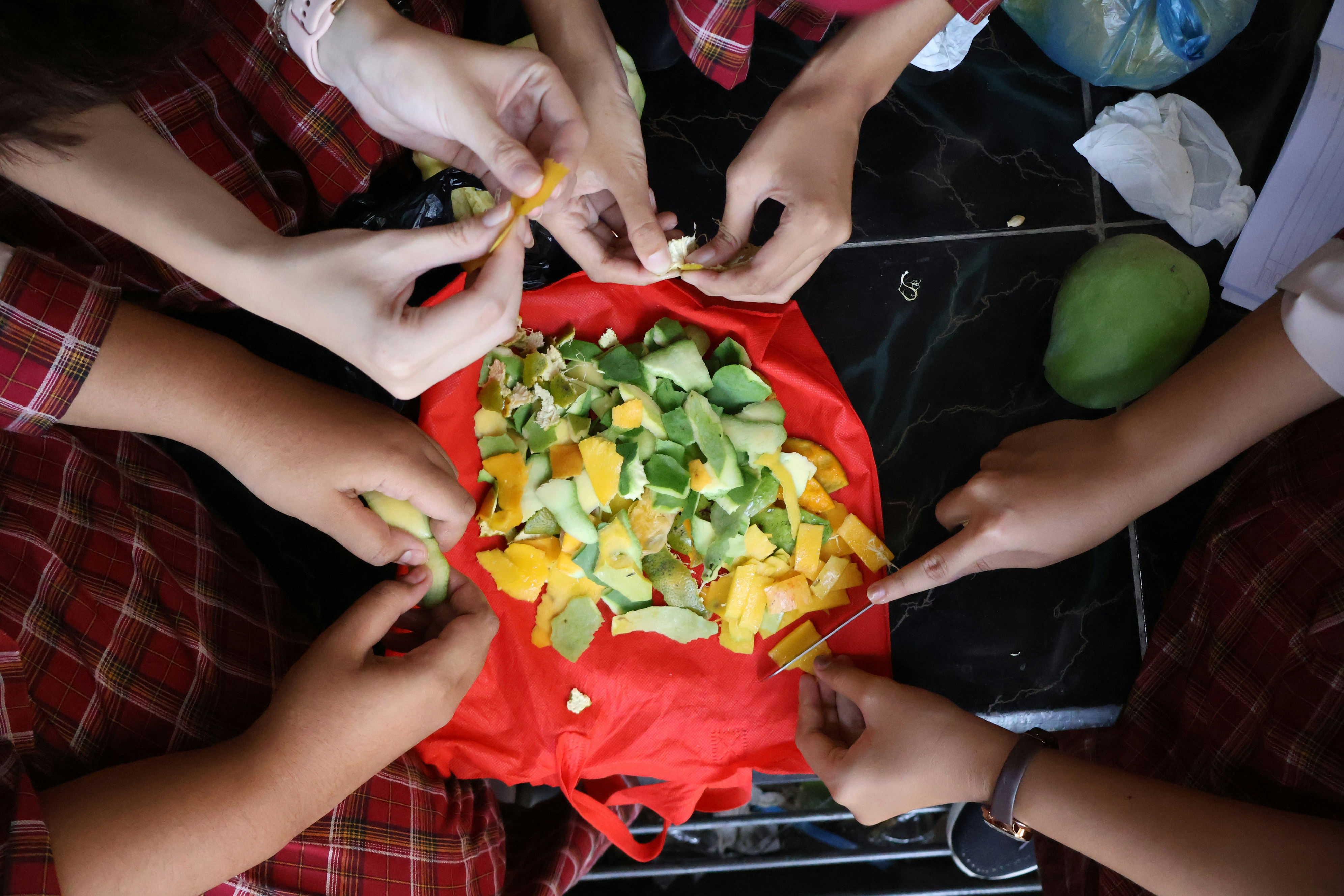 Hands at Playful Prep: A Shared Cut of Colorful Pineapple and Mango Pieces