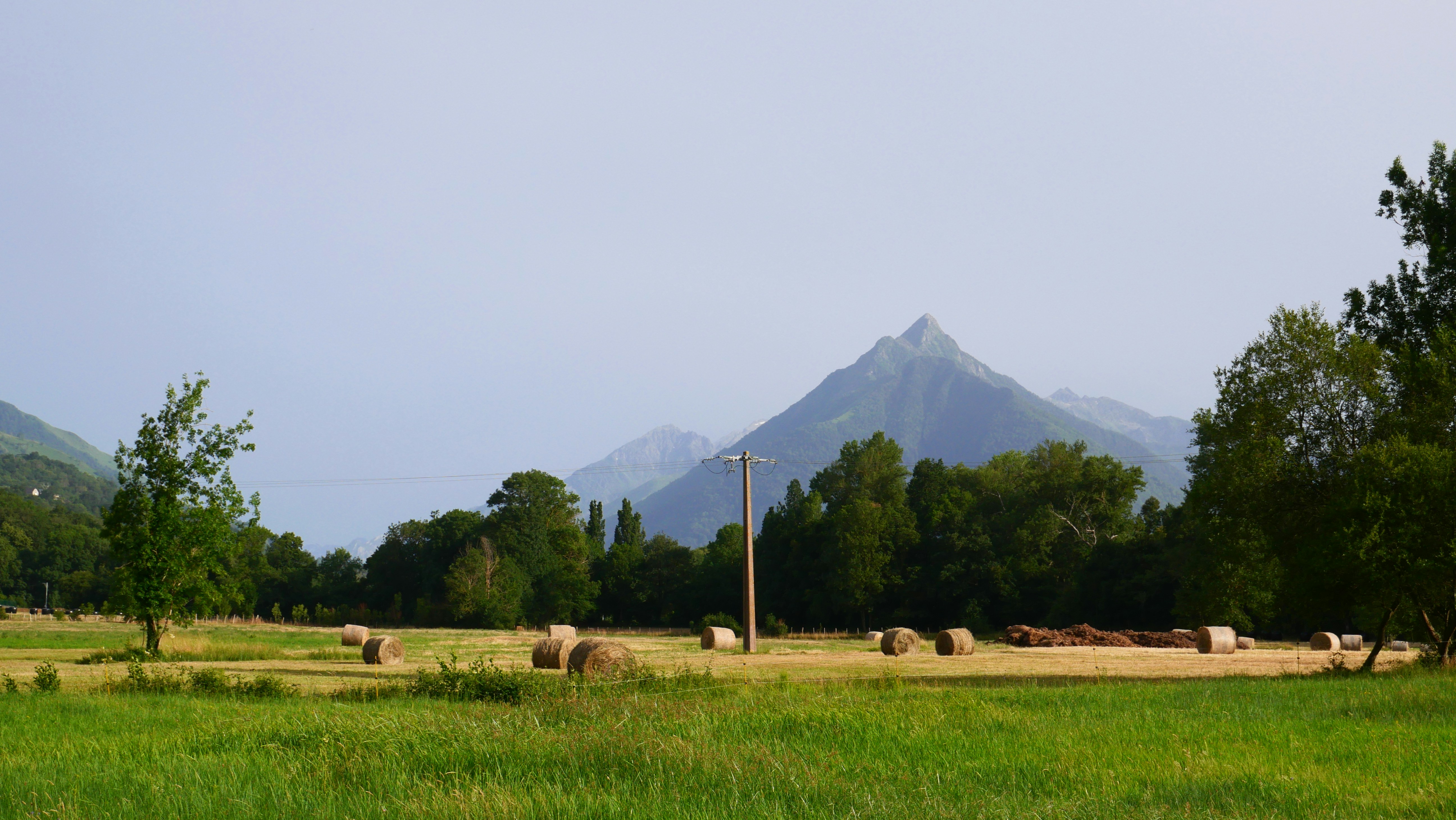 Pastoral Ridge: Hay Bales Under a Quiet Mountain Sky