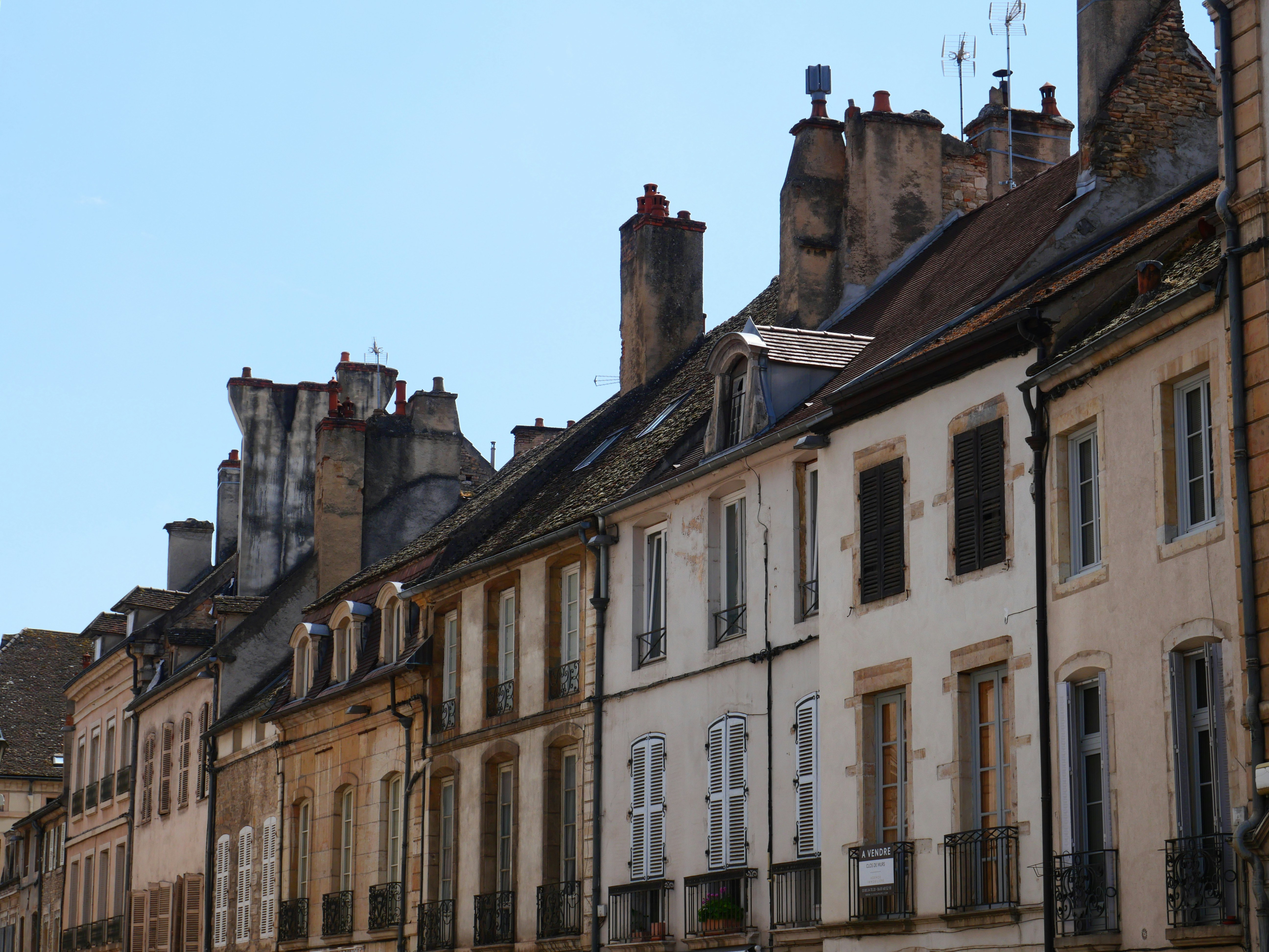 Sunlit Row: Facades and Slate Rooftops Under Clear Blue