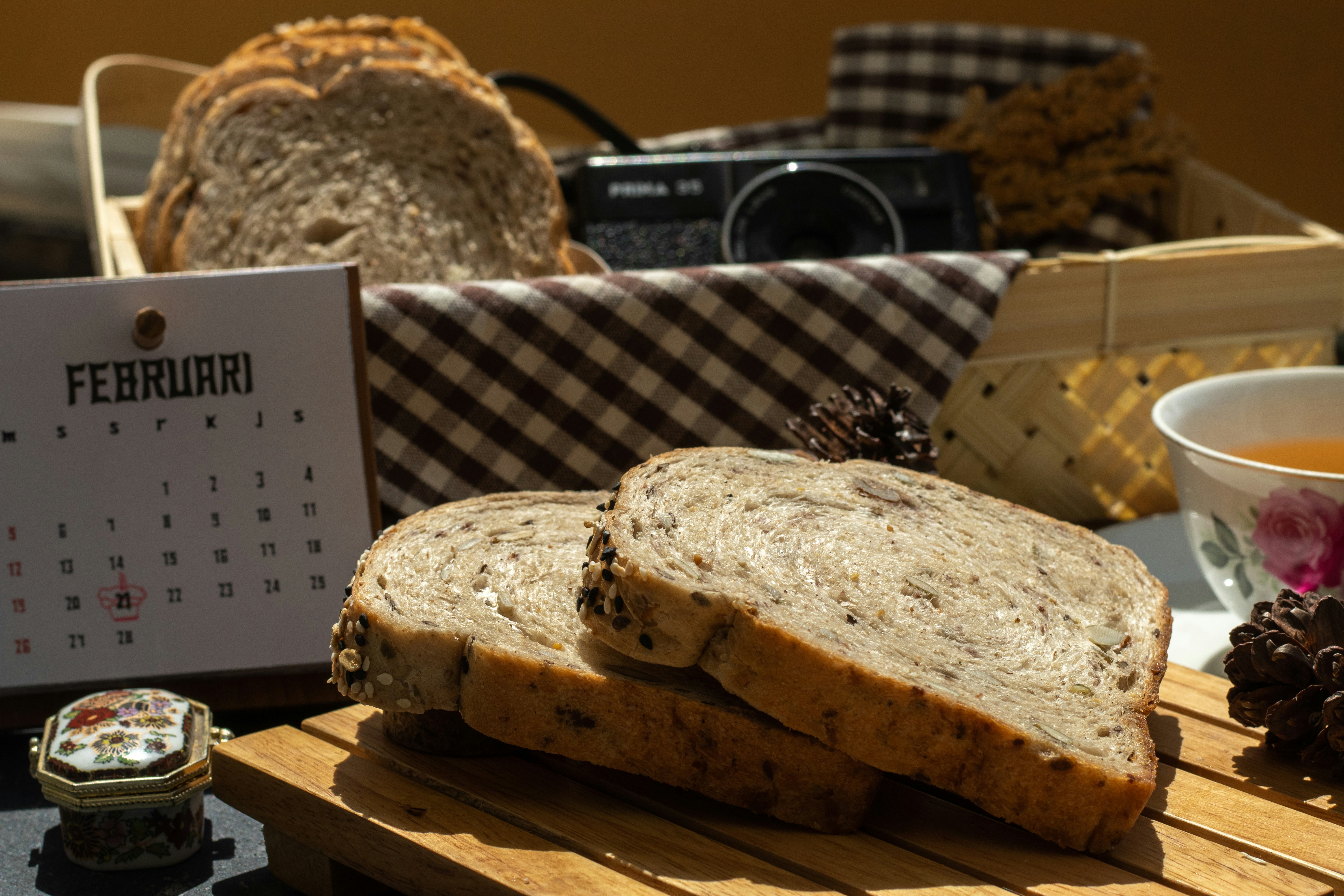 Sunlit Slices: A Rustic Bread Still Life with Tea and Pinch of Pine